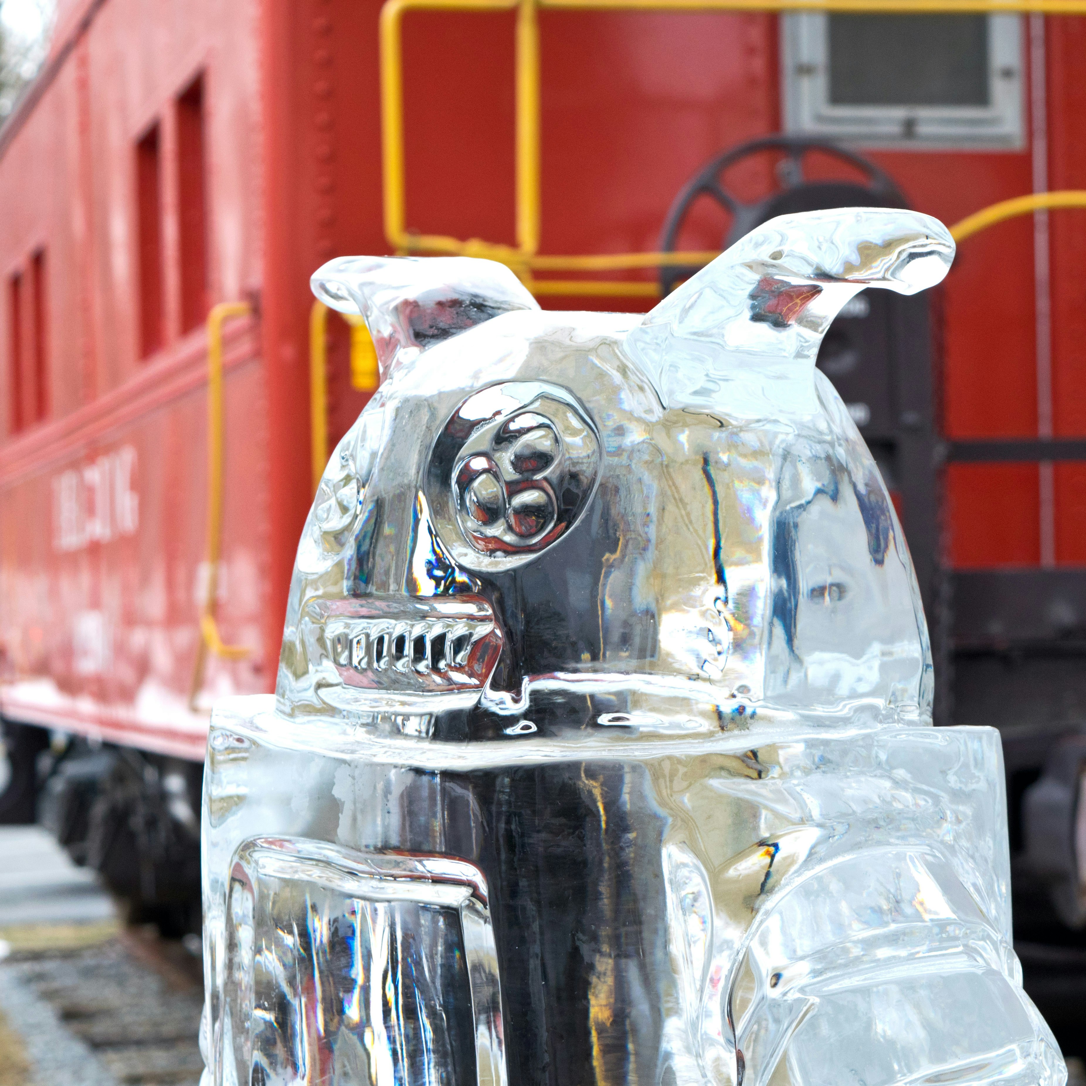 Chrome Penguin Ice Sculpture Framed by a Crimson Railcar