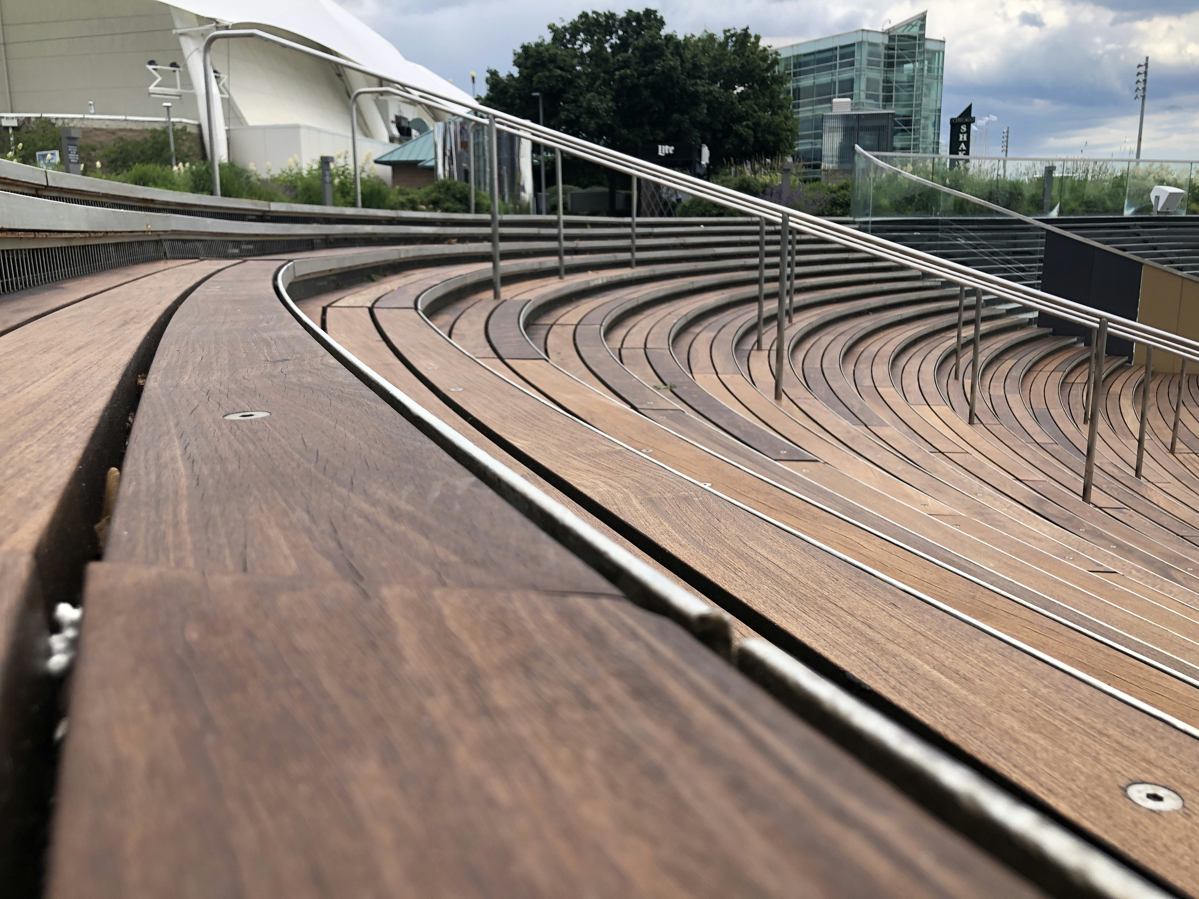 Ribbons of Wood: Curved amphitheater stairs guiding the eye toward a distant campus