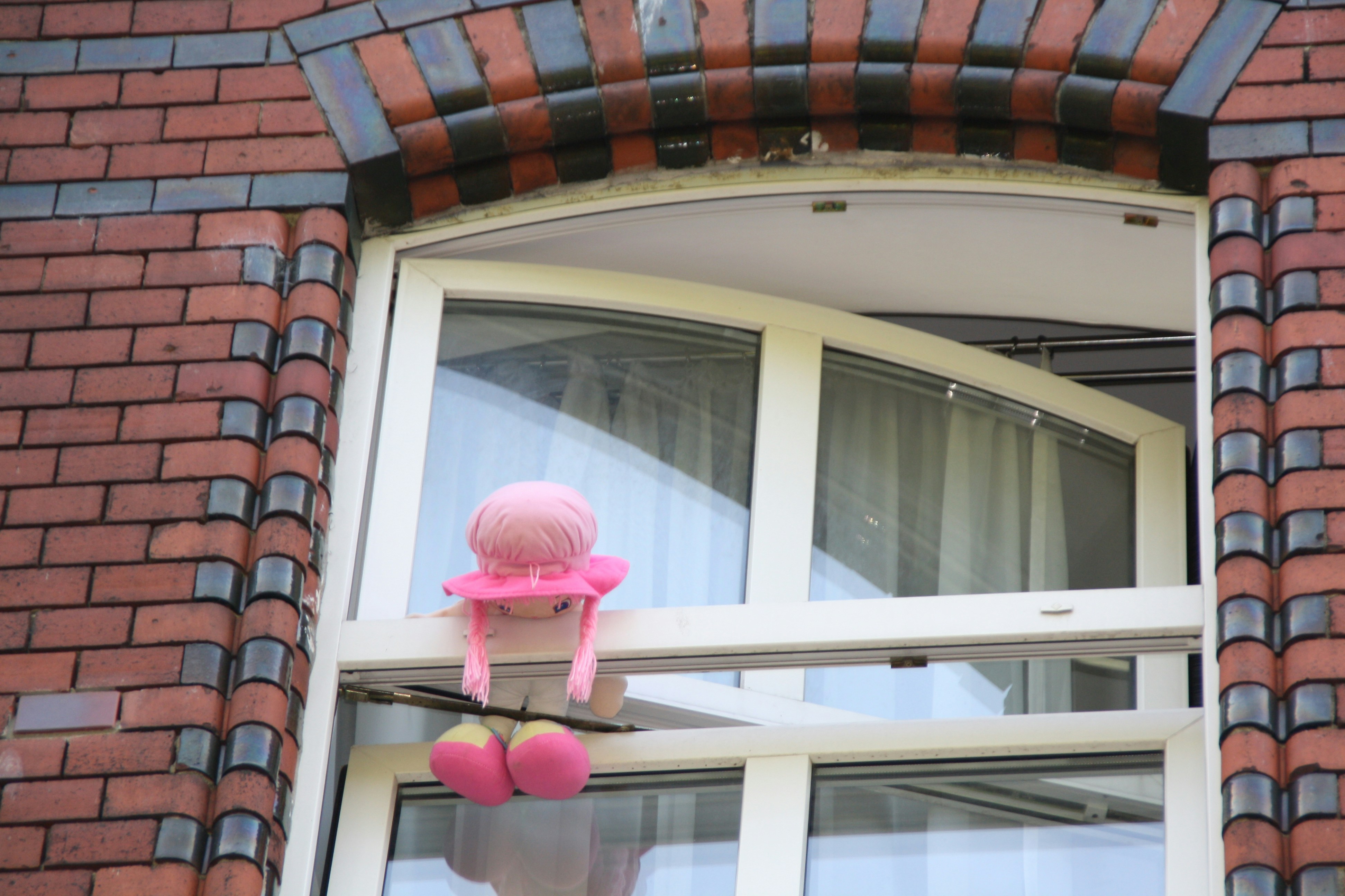 Pink Sock Puppet on a Windowsill: A Curious Balcony Portrait