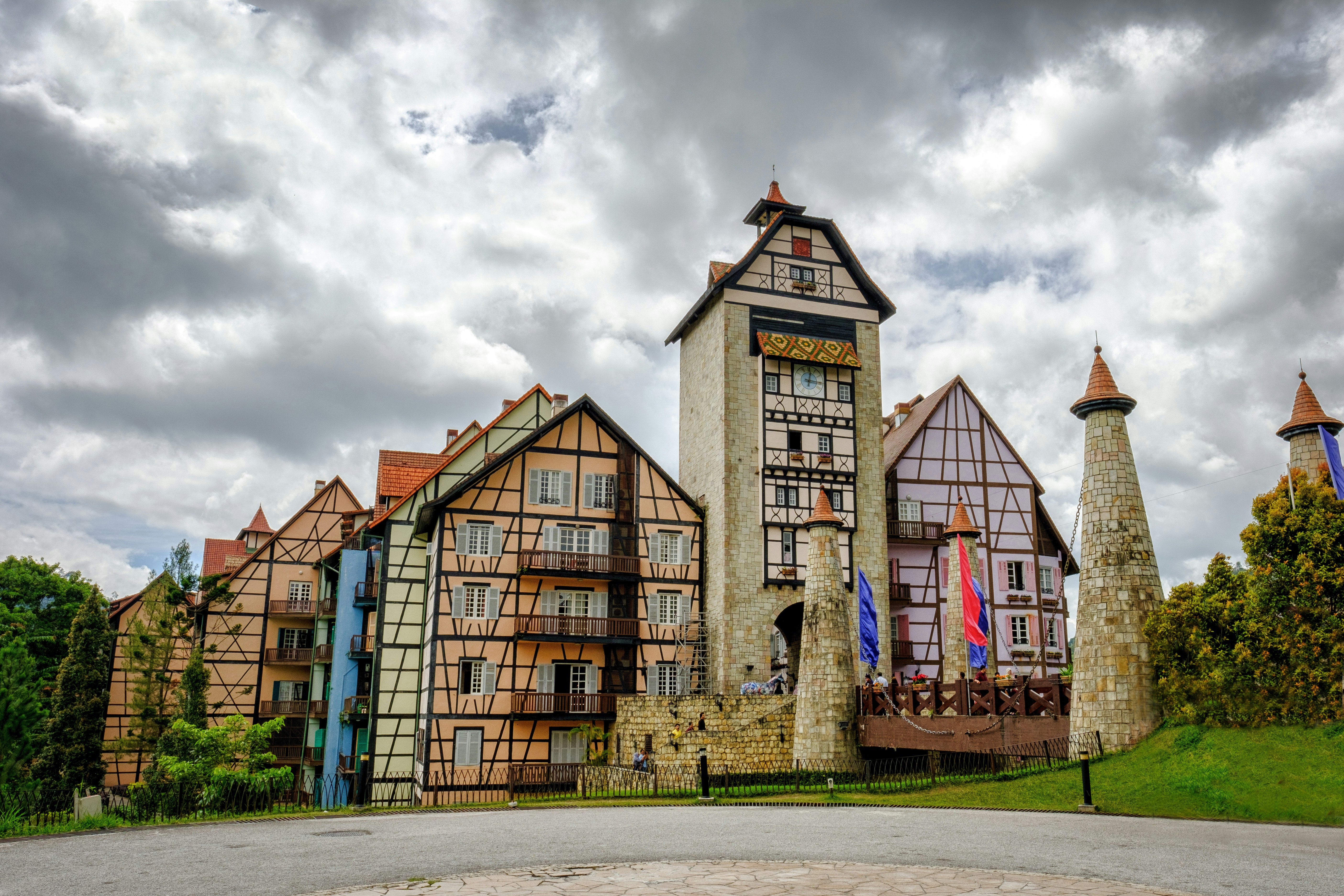 Tudor-style architecture with steep roofs and timber framing under a dramatic cloudy sky.