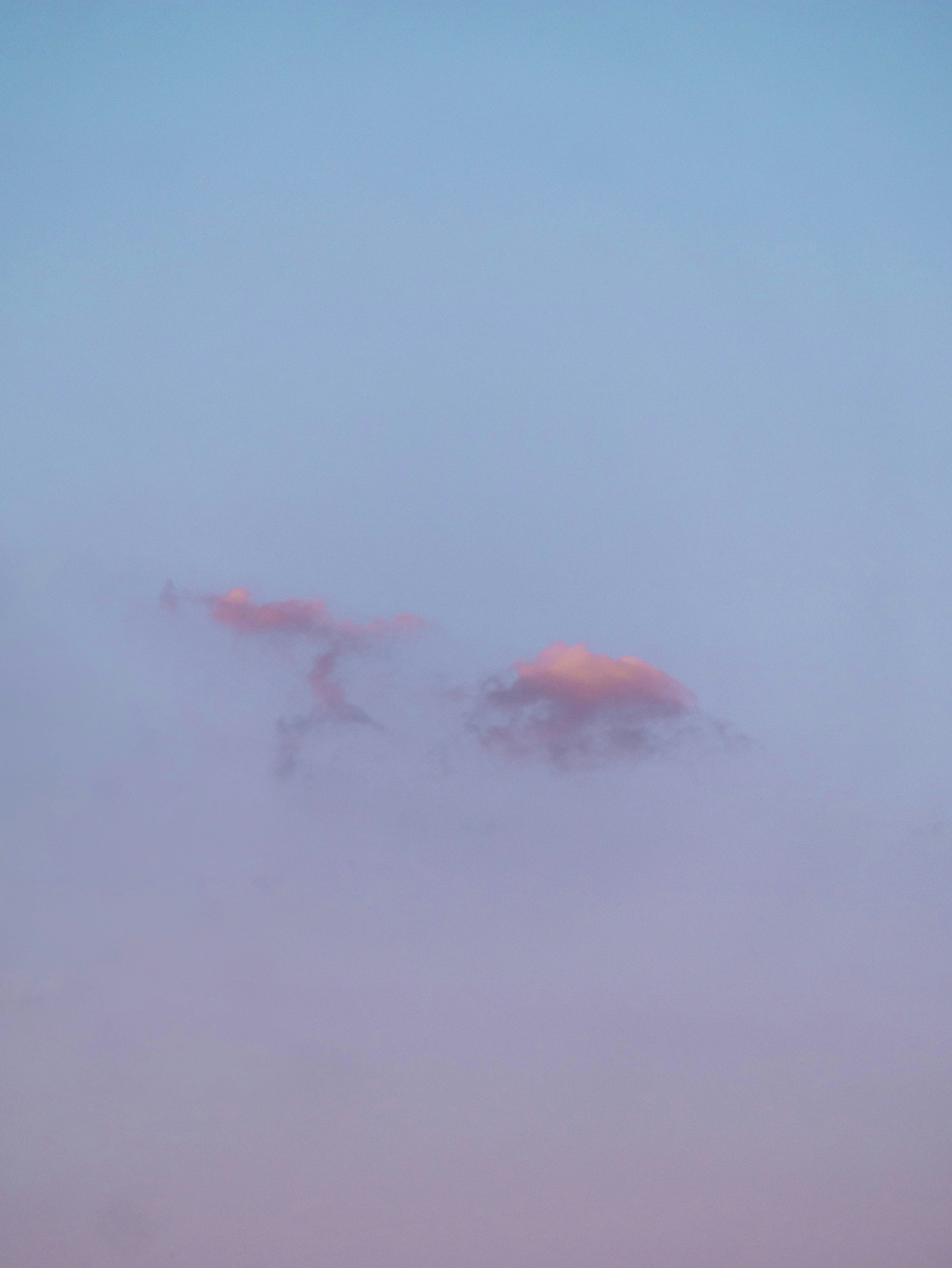 Pastel Drift: Pink-tipped Clouds in a Quiet Sky
