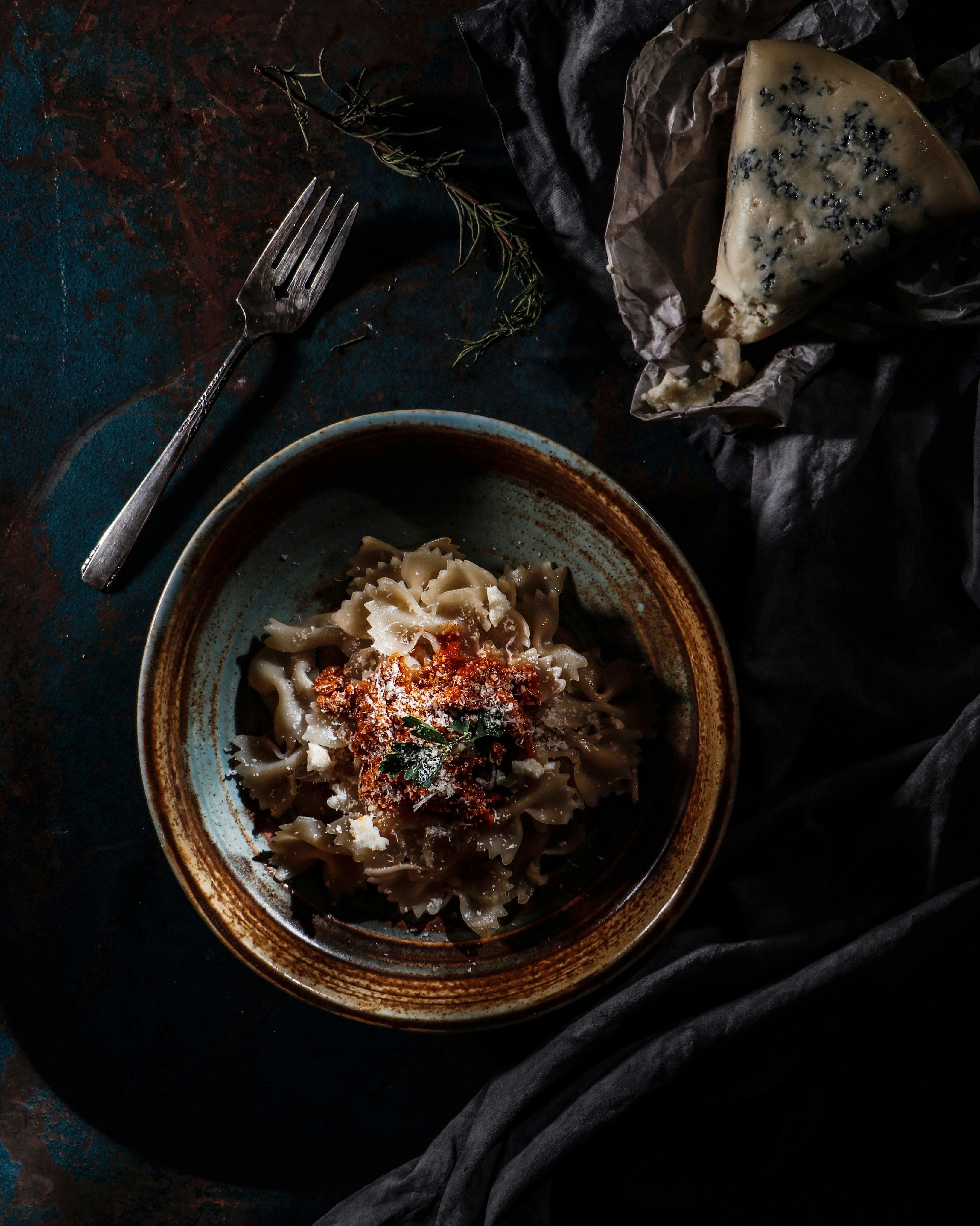 Rustic Pasta Portrait: A Plate of Farfalle with Herb Garnish under Moody Lighting