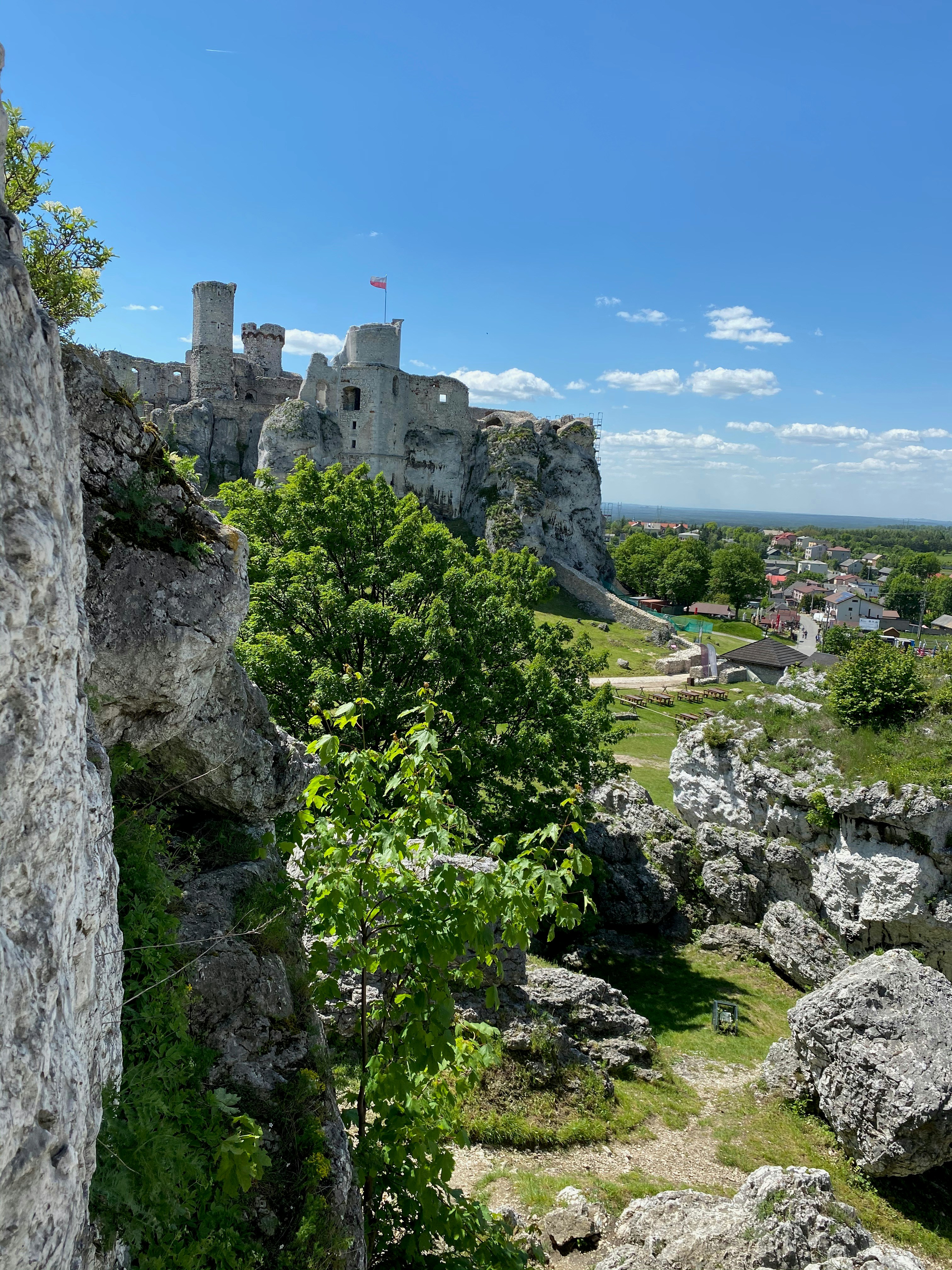 Ancient castle ruins perched atop a rocky outcrop, surrounded by lush greenery and a clear blue sky. A glimpse into the past amidst modern landscapes.