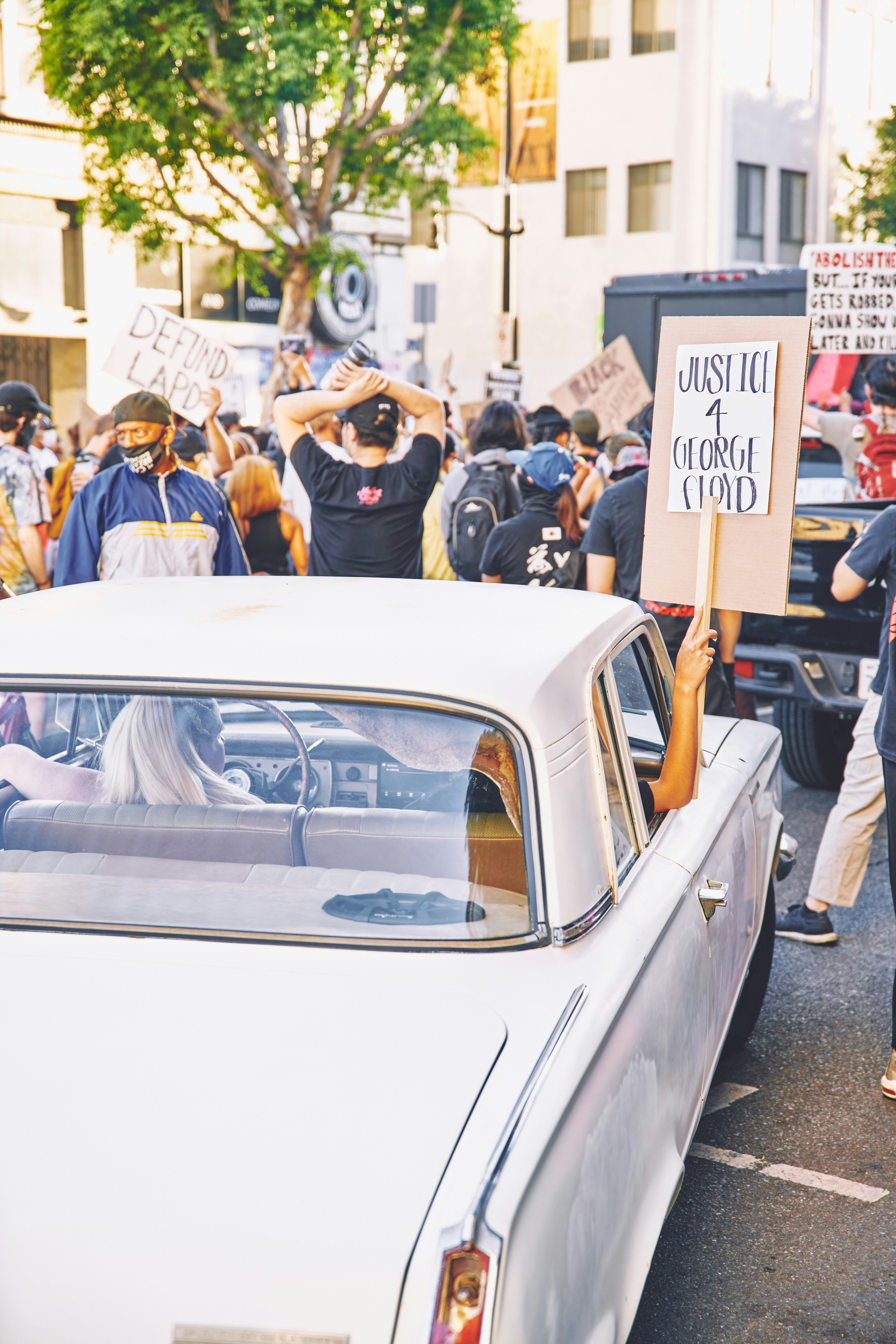 City Street Rally: Hands Raised for Justice by a Classic Car