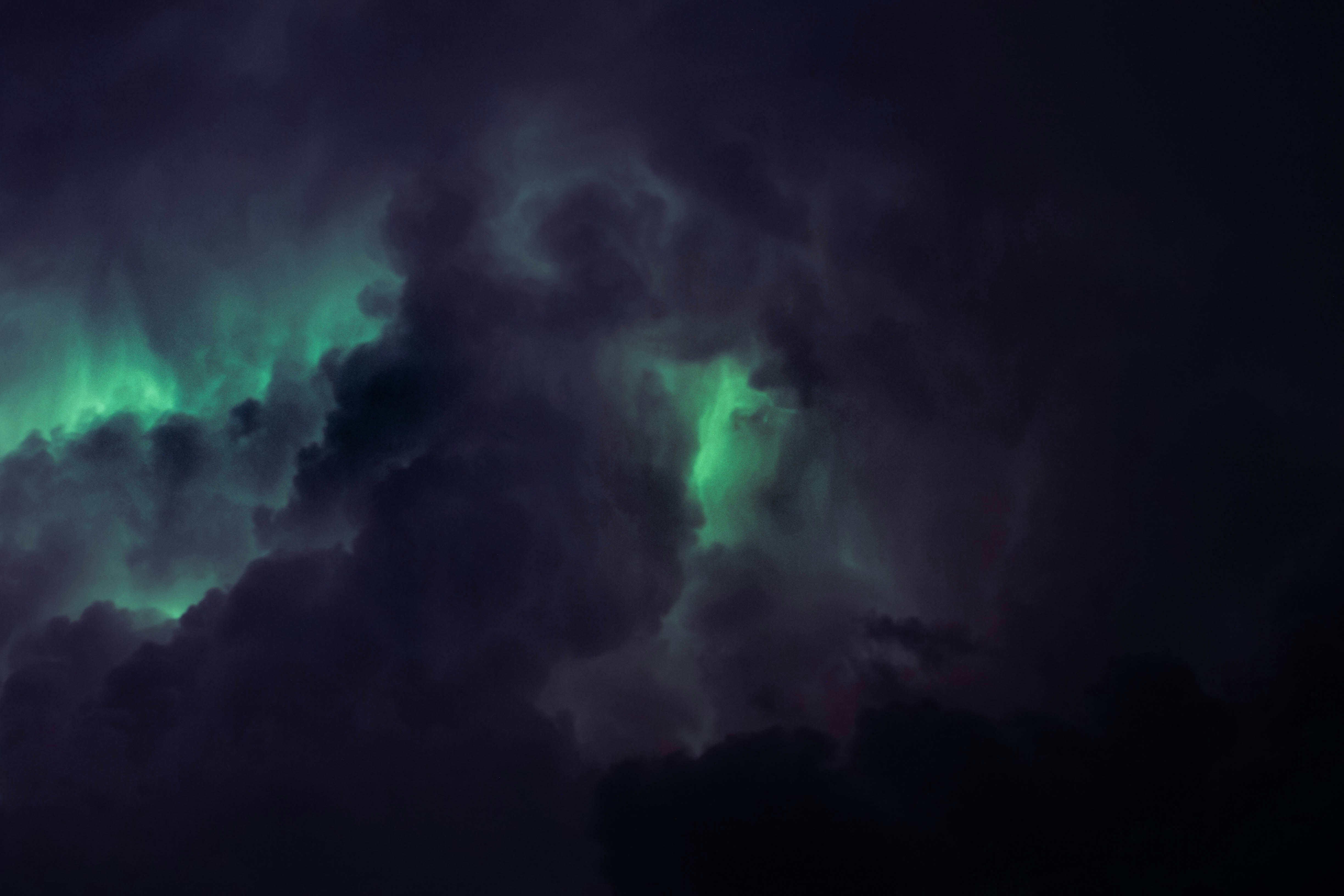 Dark storm clouds illuminated by an ethereal green light.
