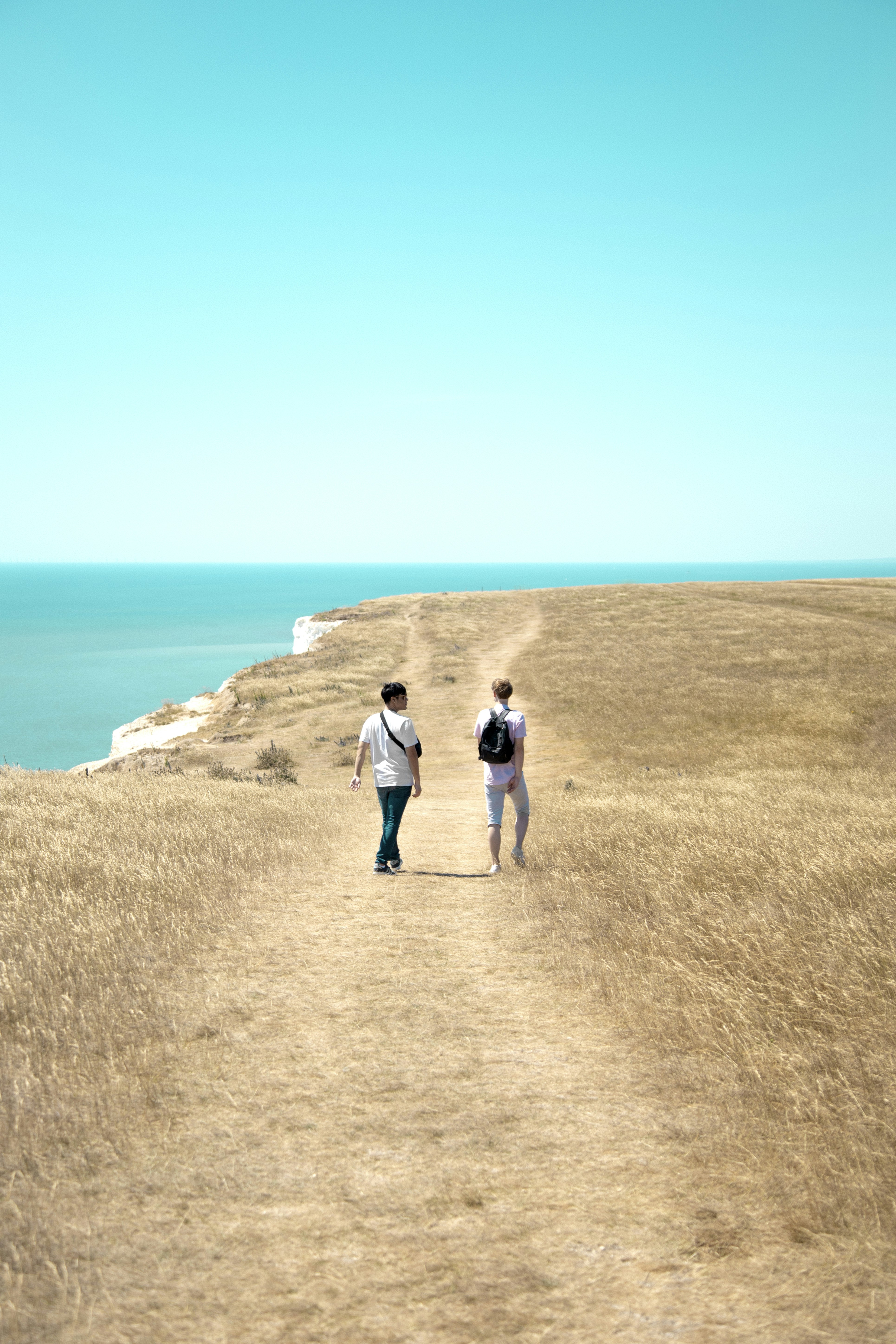 Trail to the Horizon: Two Hikers Along a Sunlit Coastal Bluff