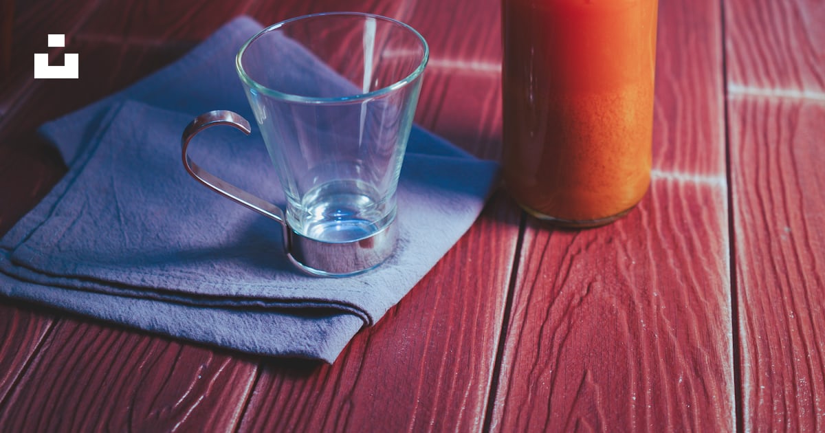 Clear Glass Bottle Beside Clear Drinking Glass On Brown Wooden Table