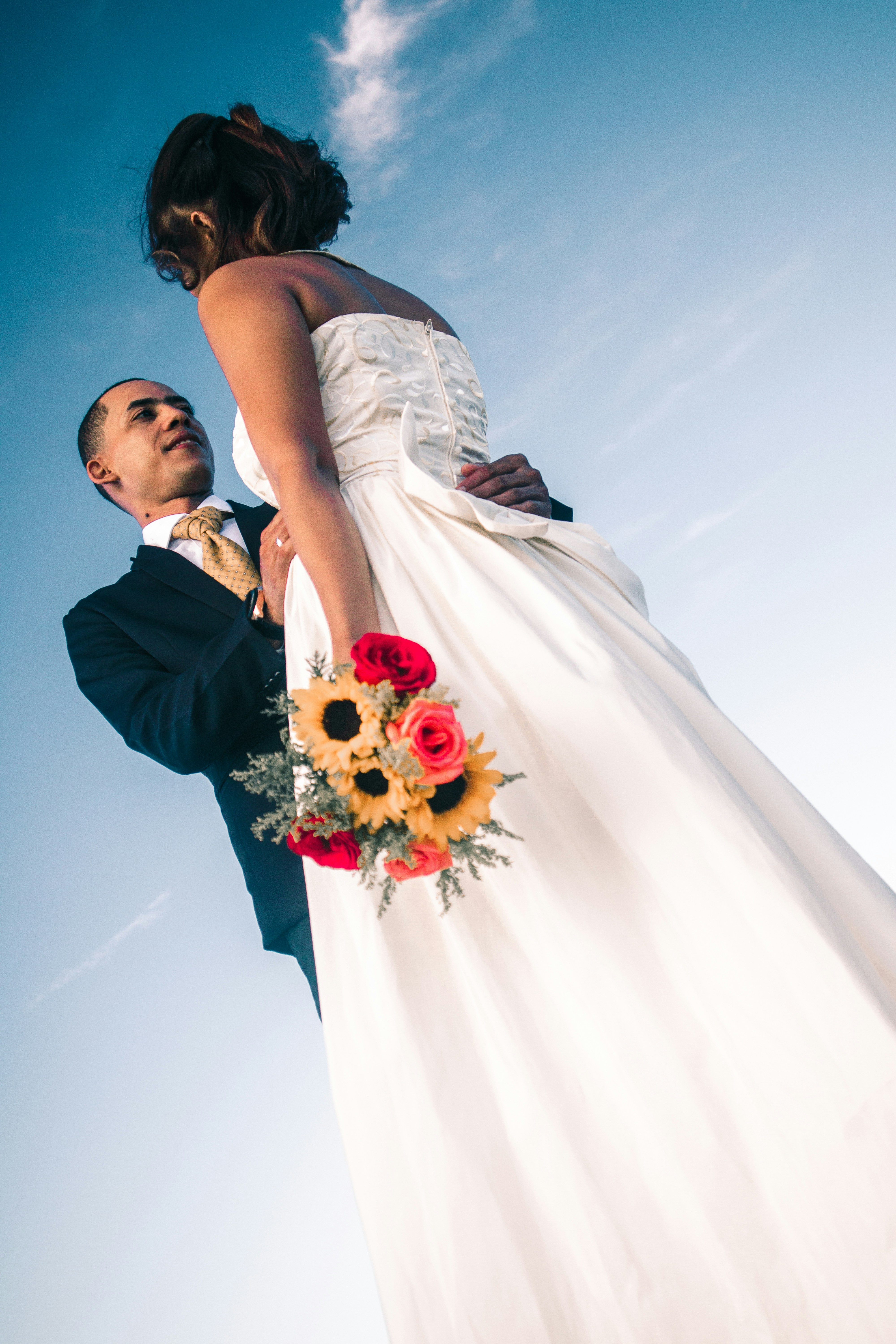 man and woman kissing under blue sky during daytime