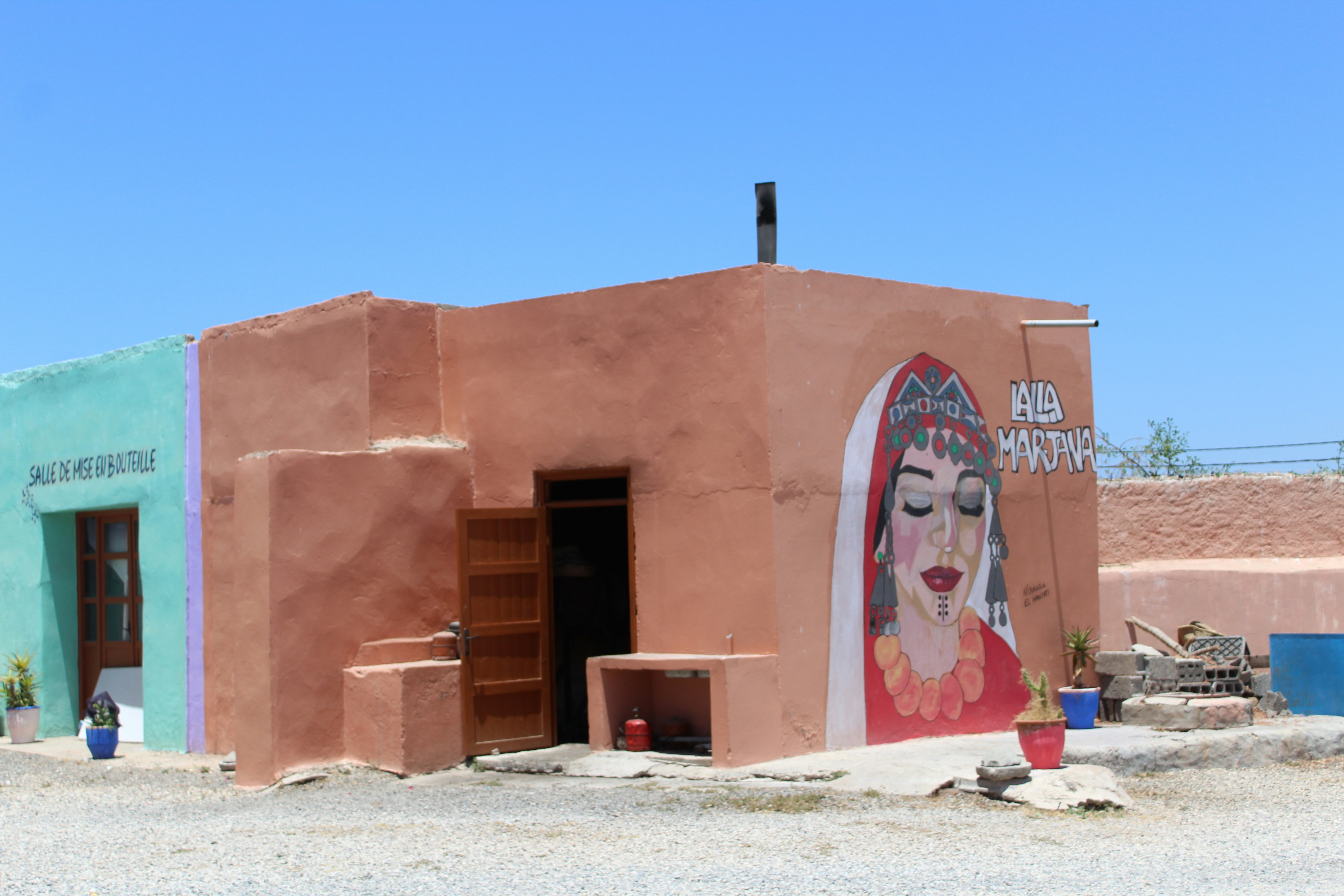 Sunlit Adobe Facade with a Portrait Mural Under a Clear Desert Sky