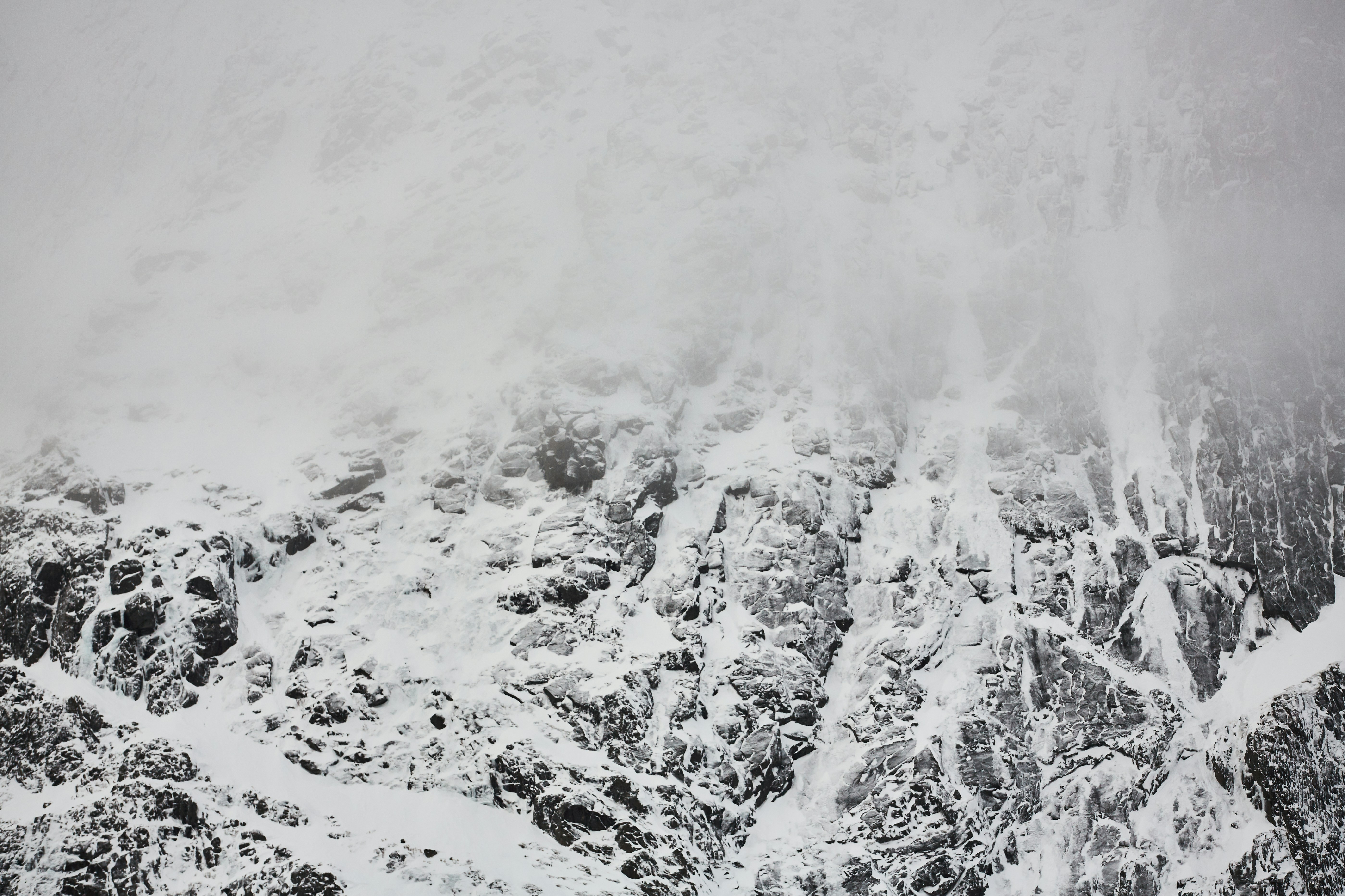 Mist Veil over Granite: Snow-Crowned Ridge in Low Light