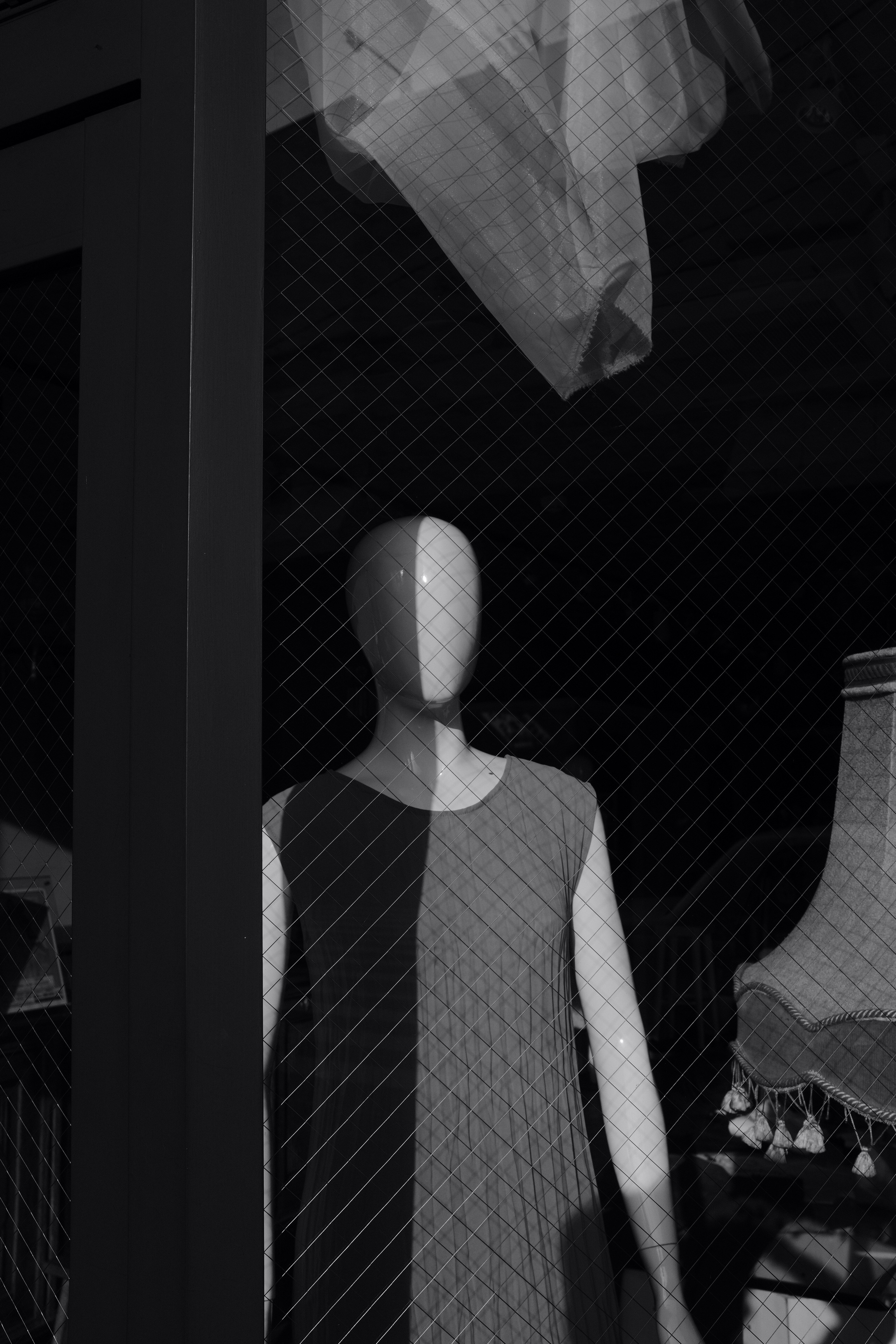 Grayscale Silhouette Behind a Diamond Window: A Faceless Mannequin in Focus