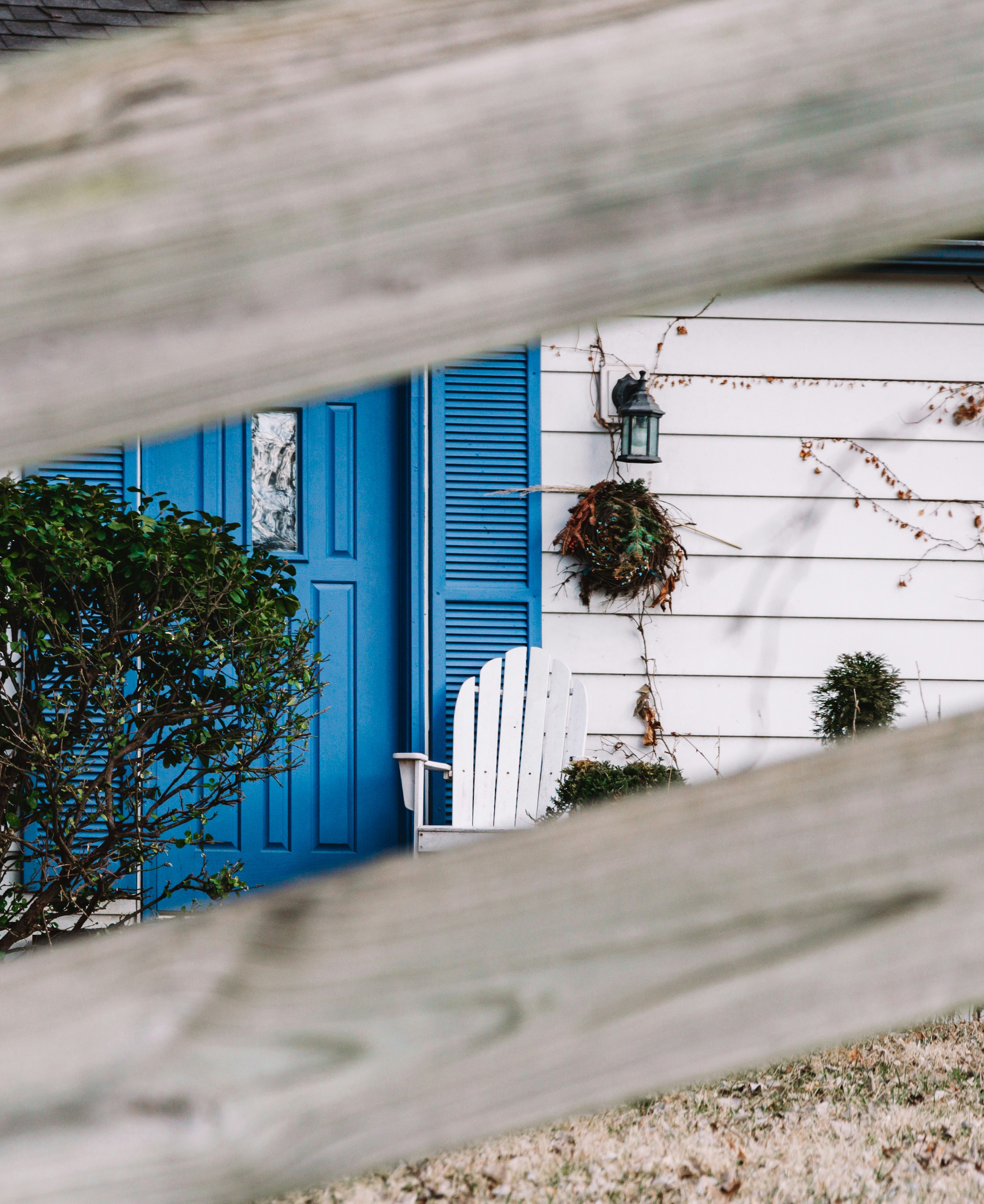 Blue Door in Focus: A Quiet Porch Scene Framed by Weathered Slats