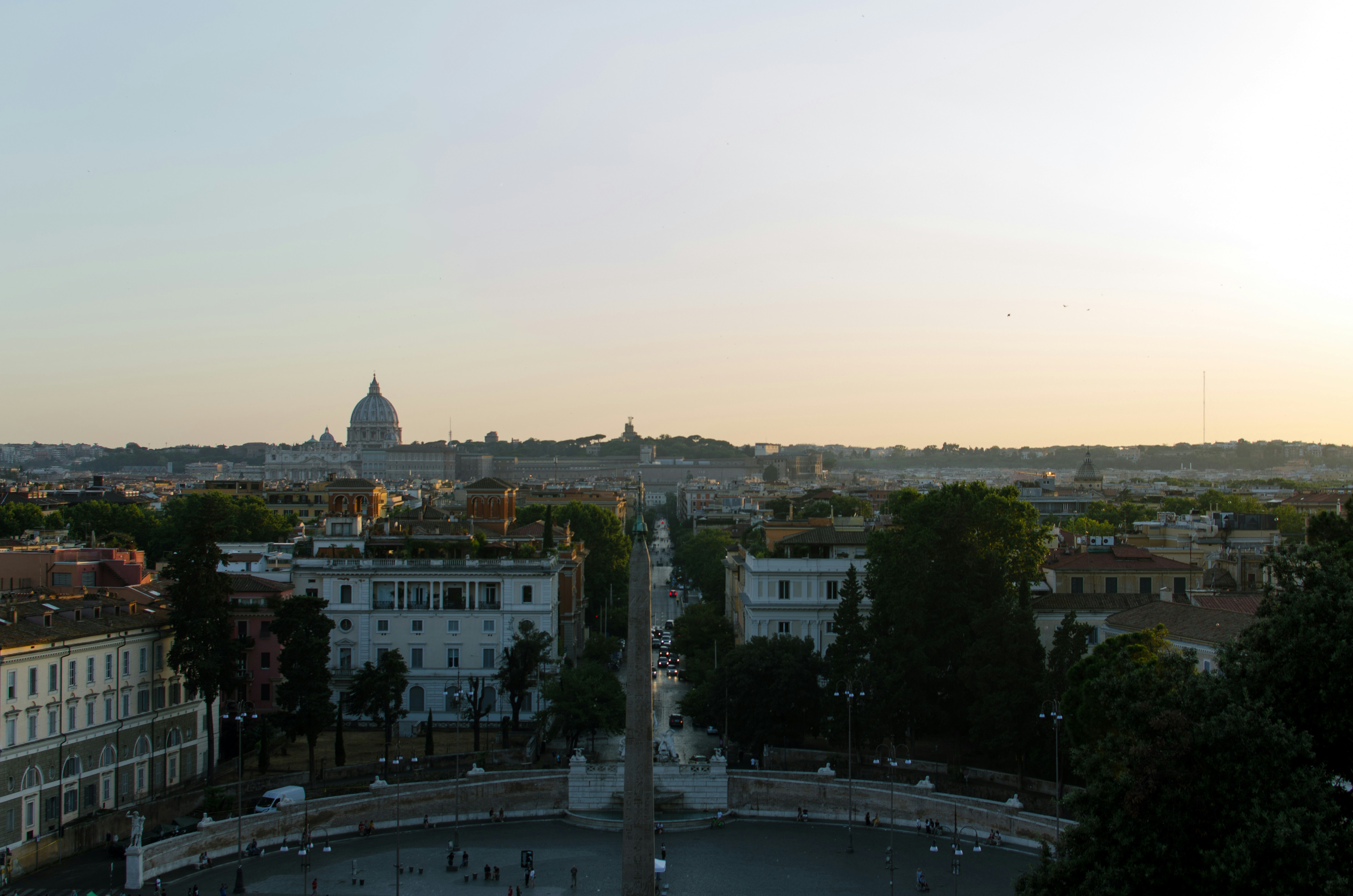 Panoramic view of Rome at sunset, showcasing the silhouette of St. Peter's Basilica against a pastel sky.