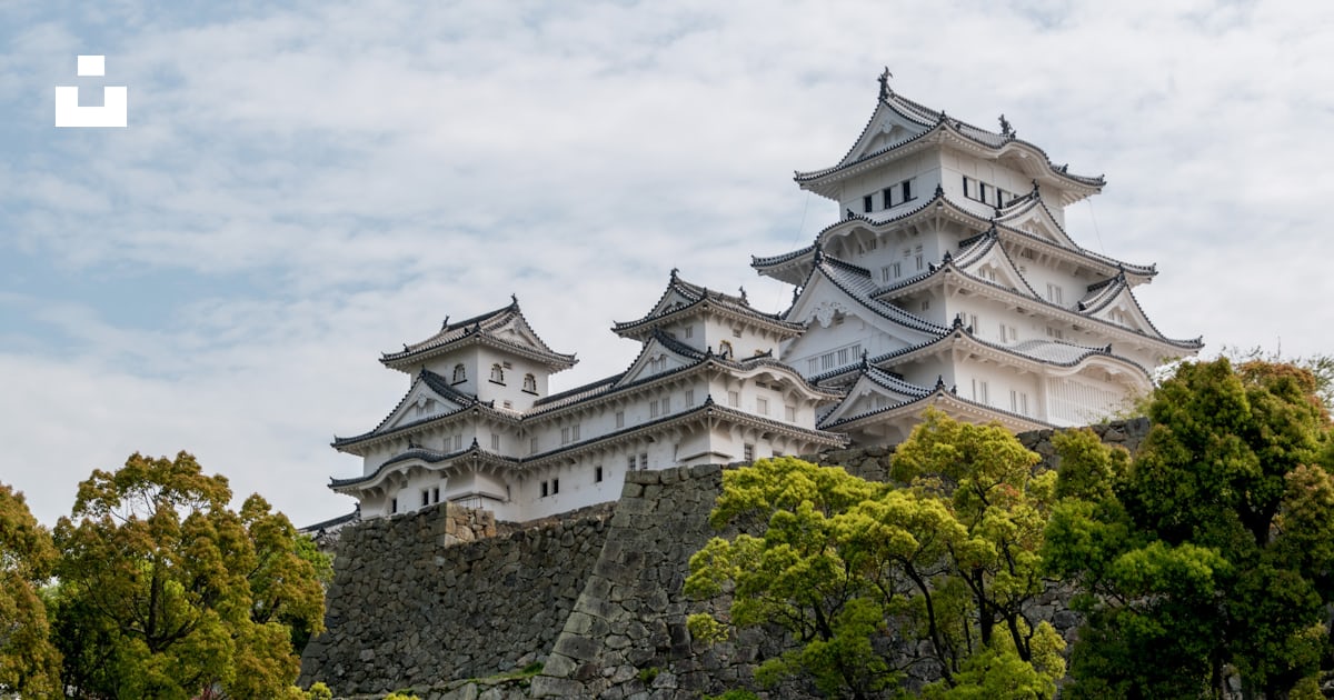 昼間は白い雲の下に緑の木々に囲まれた白と灰色のコンクリートの城の写真 Unsplashの無料日本写真