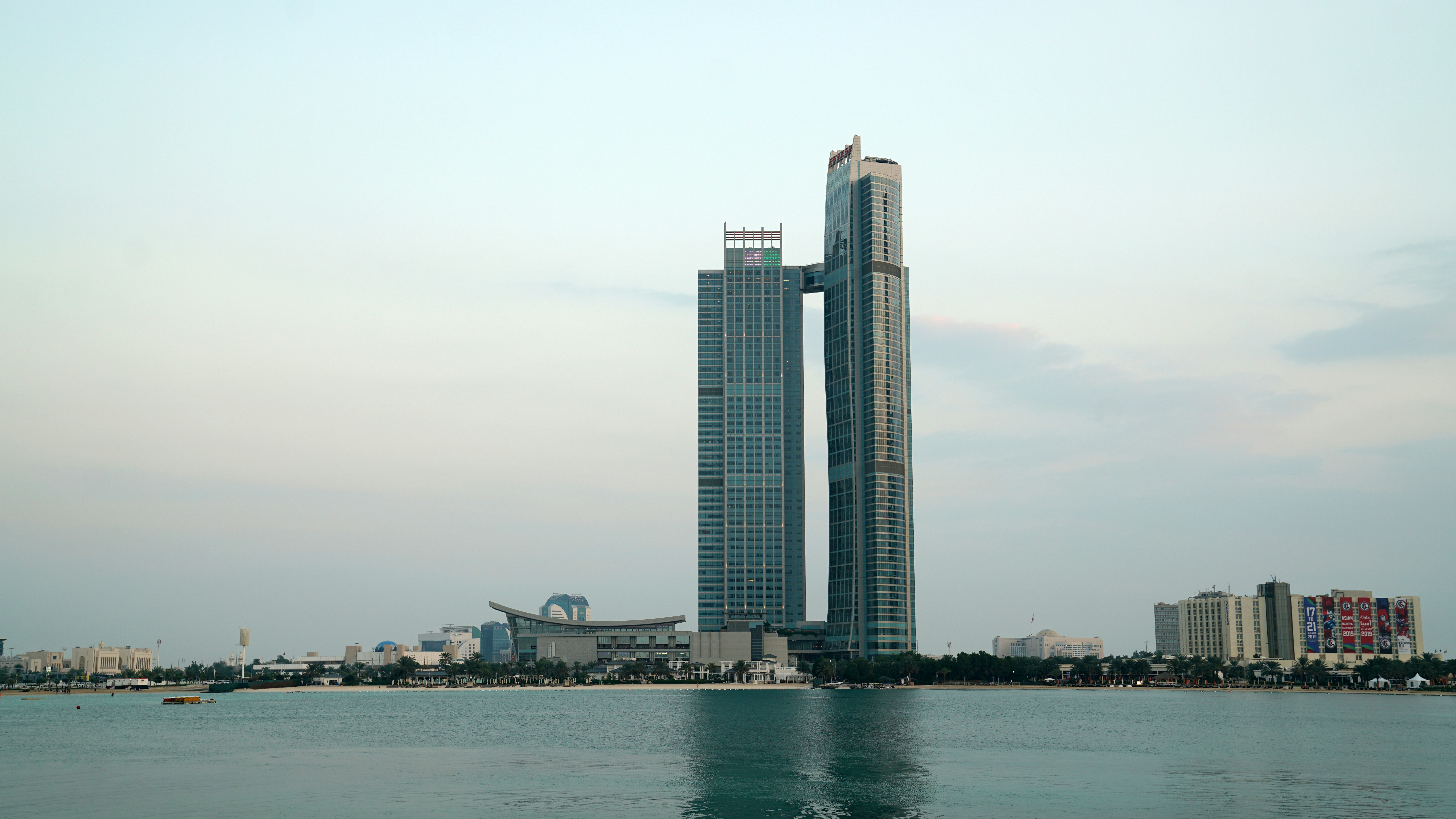 Two modern skyscrapers rise majestically against a serene waterfront backdrop, showcasing contemporary architectural design.