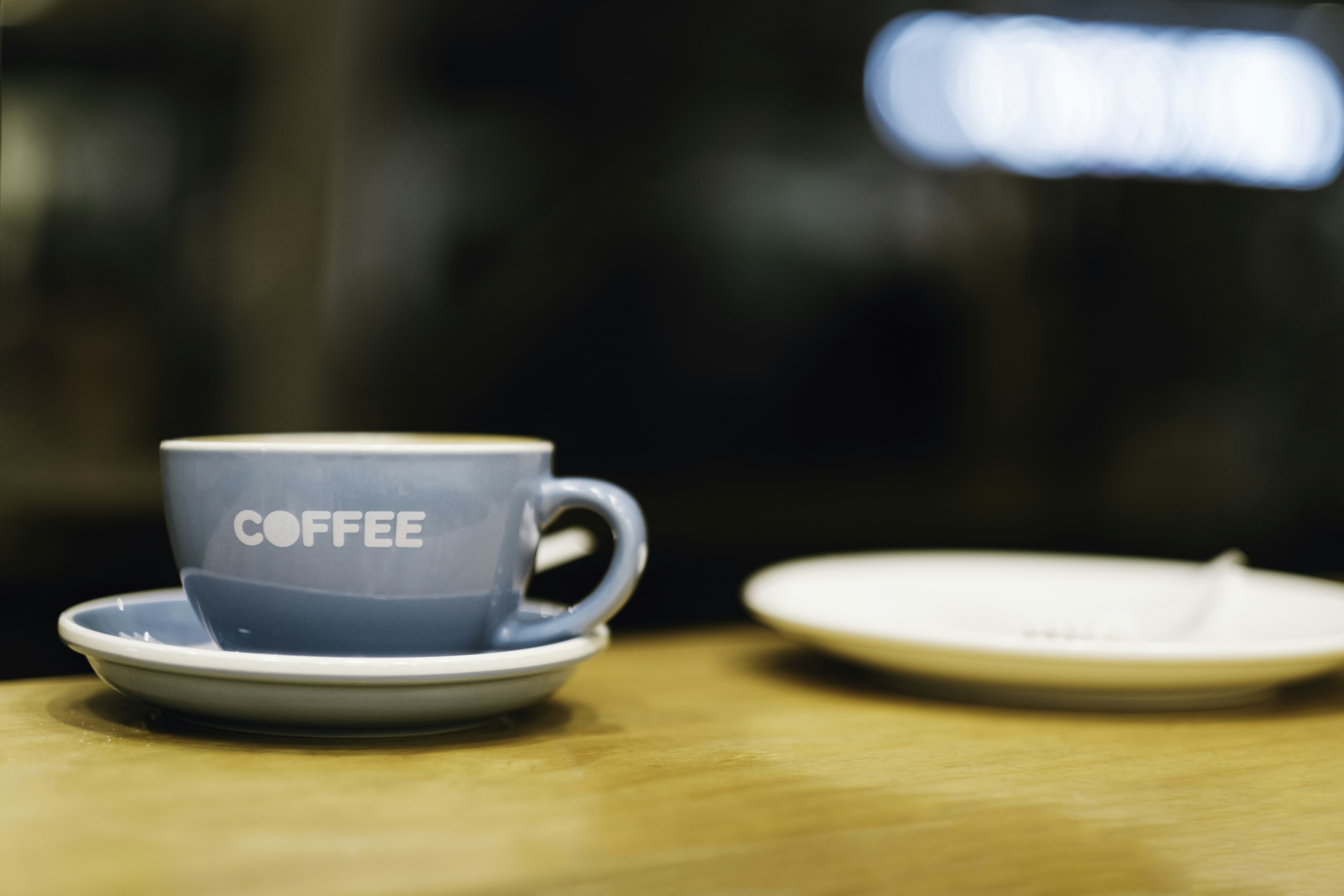 Blue coffee cup on a wooden table with blurred background.