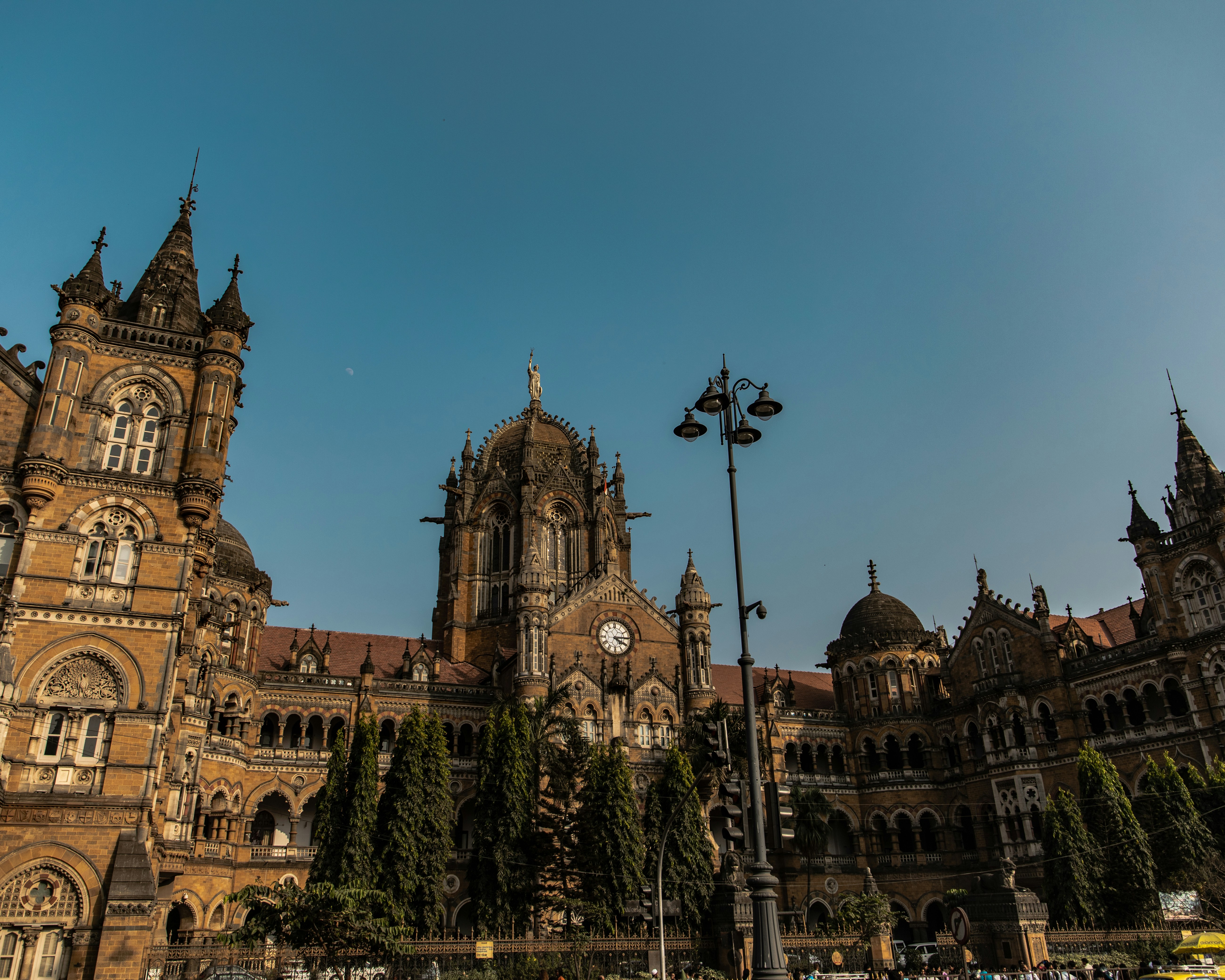 Ornate Victorian Gothic building with intricate details and a prominent clock tower beneath a clear blue sky.