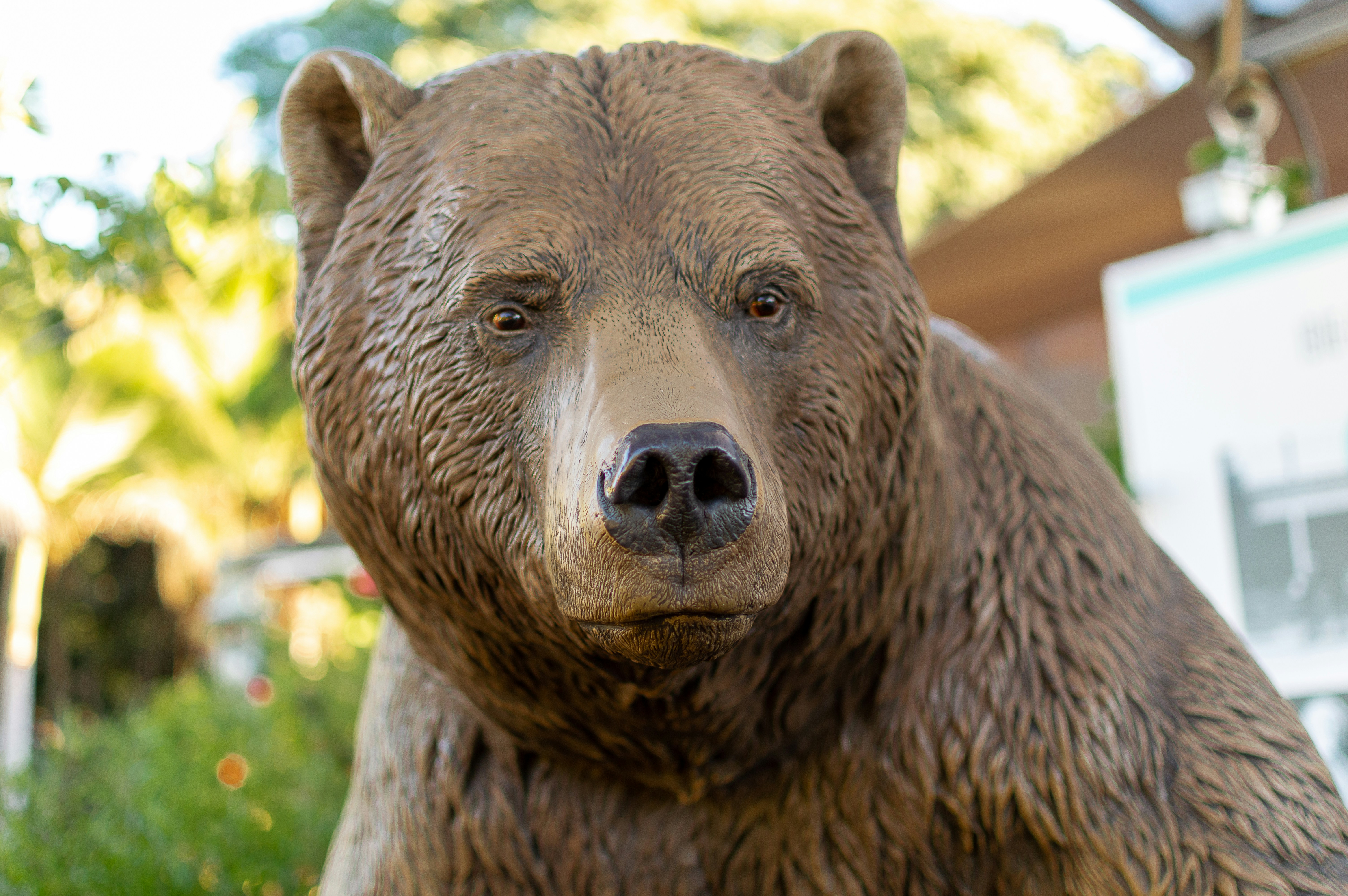 Close-up of a brown bear statue with a textured fur surface in an outdoor exhibit