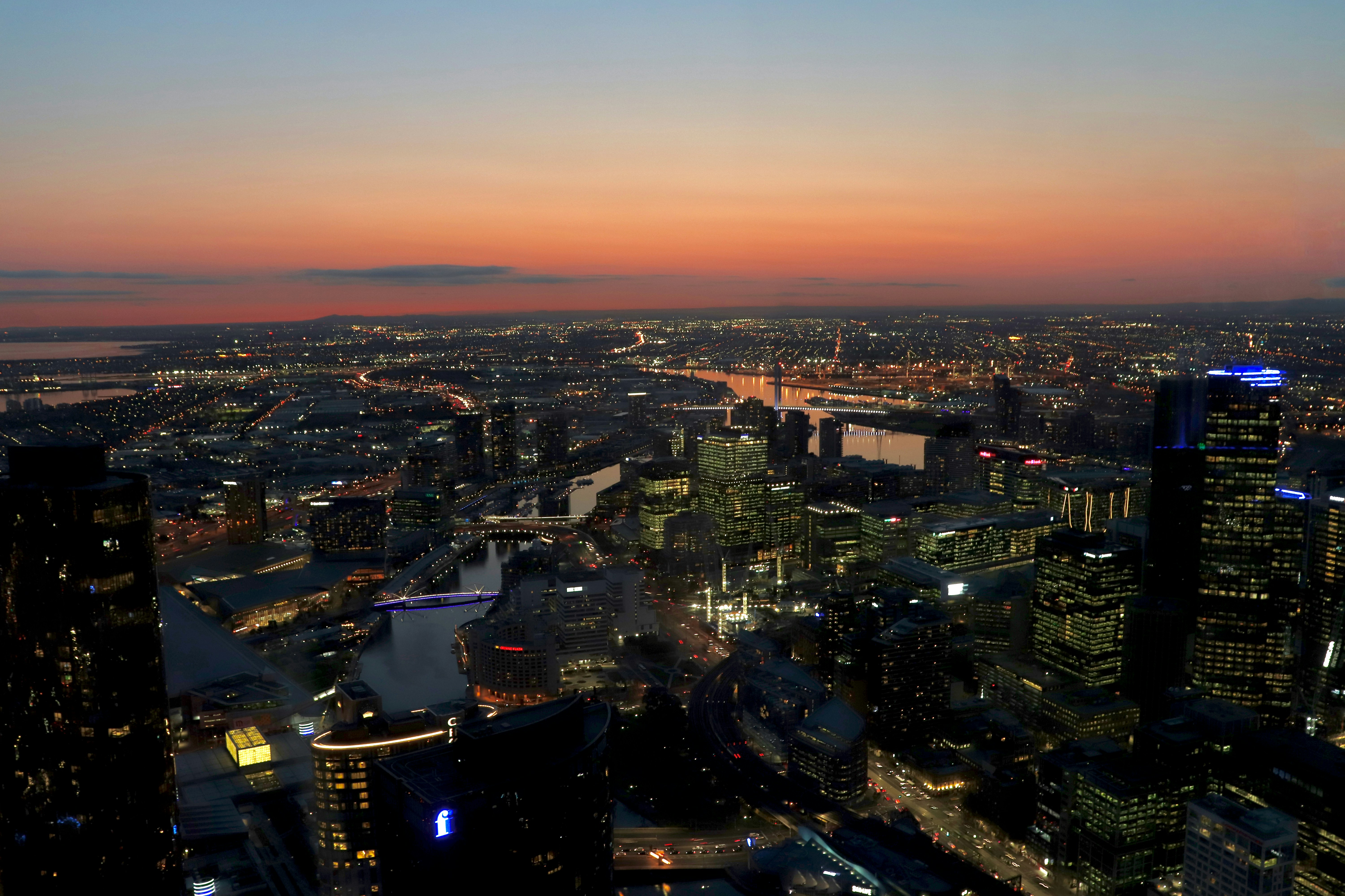 Vibrant cityscape illuminated at dusk, showcasing the interplay of lights and shadows across the skyline and waterways.