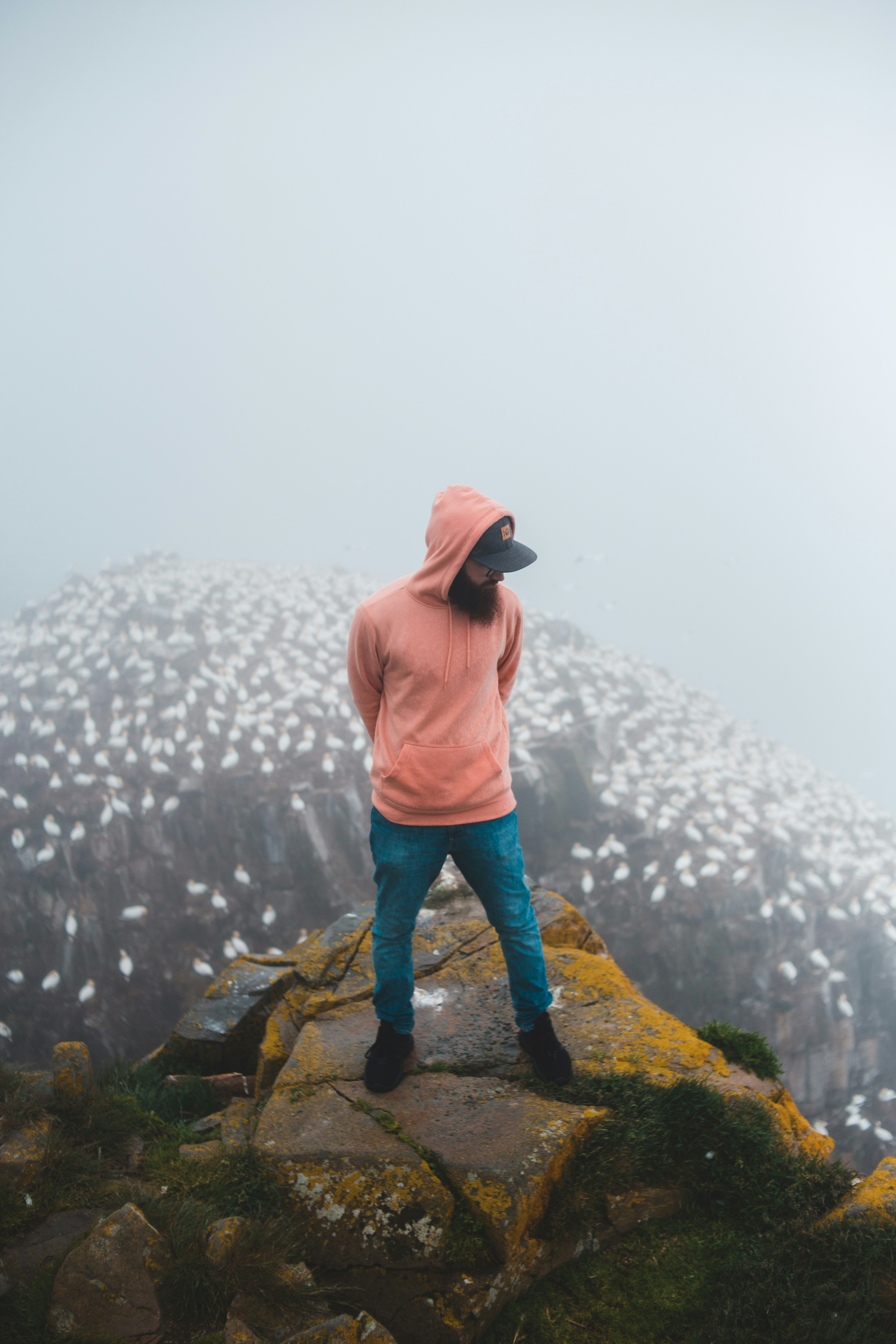 Man in pink dress shirt and blue denim jeans standing on rock formation ...