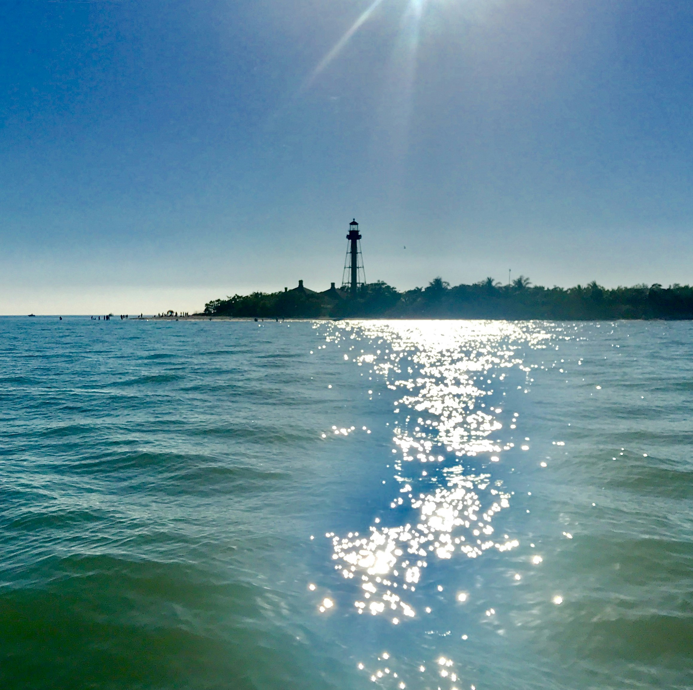Beacon at the Quiet Horizon: Sunlit Ripples and a Sapphire Sea