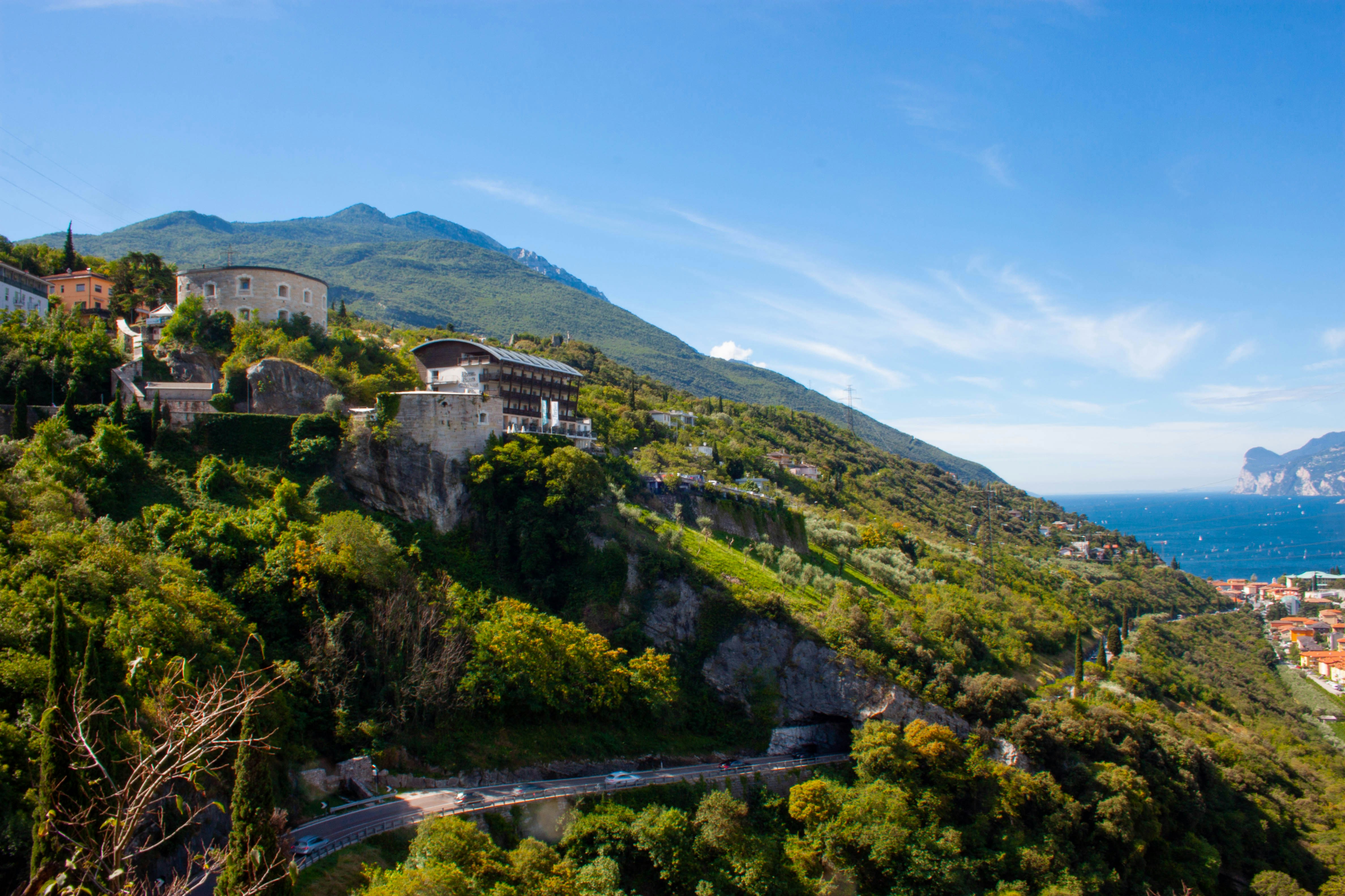 Lush green hillside overlooking a coastal town with the sea in the distance under a clear blue sky.