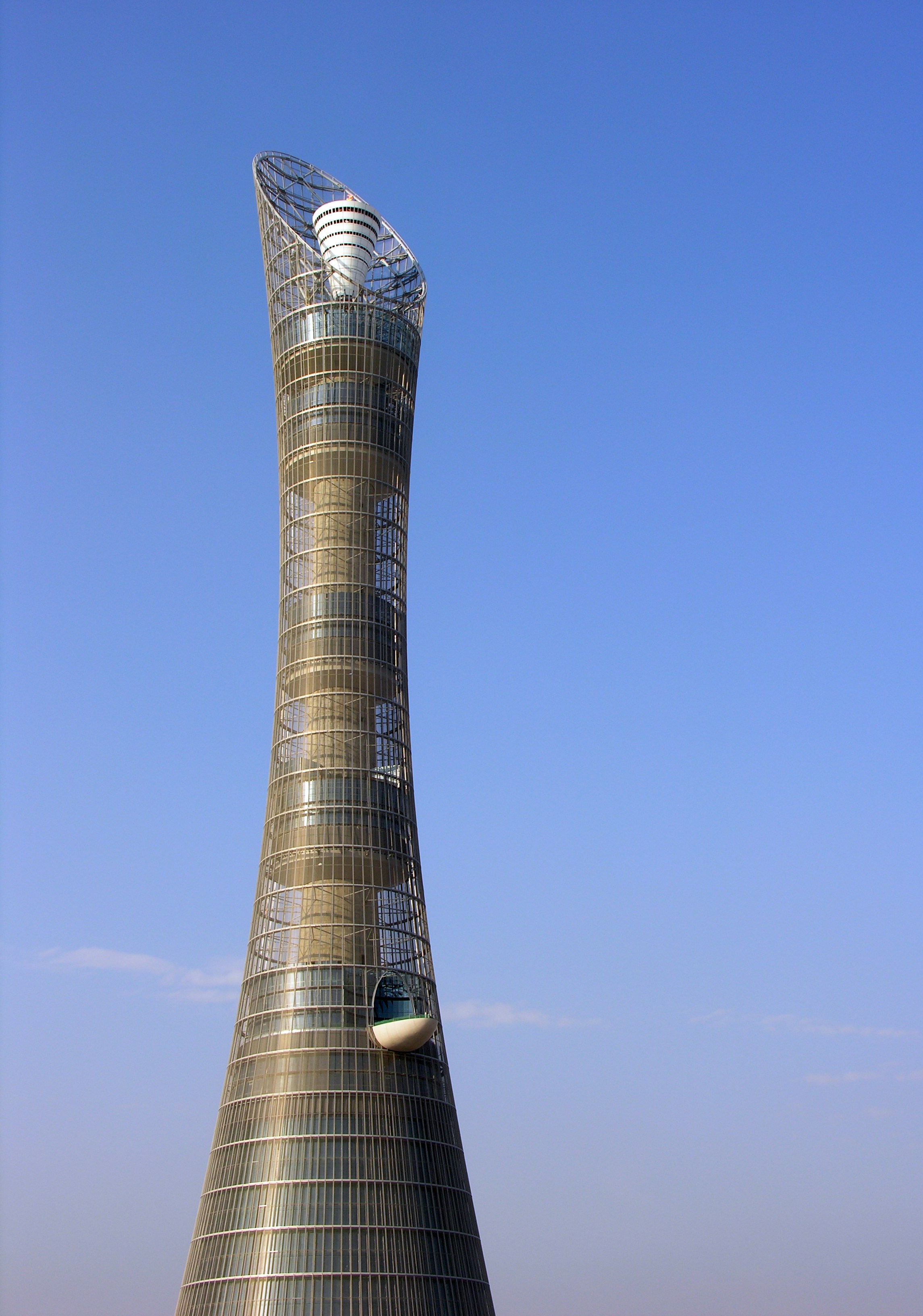 A futuristic tower with a distinctive twisting design stands against a clear blue sky, showcasing modern architectural innovation.