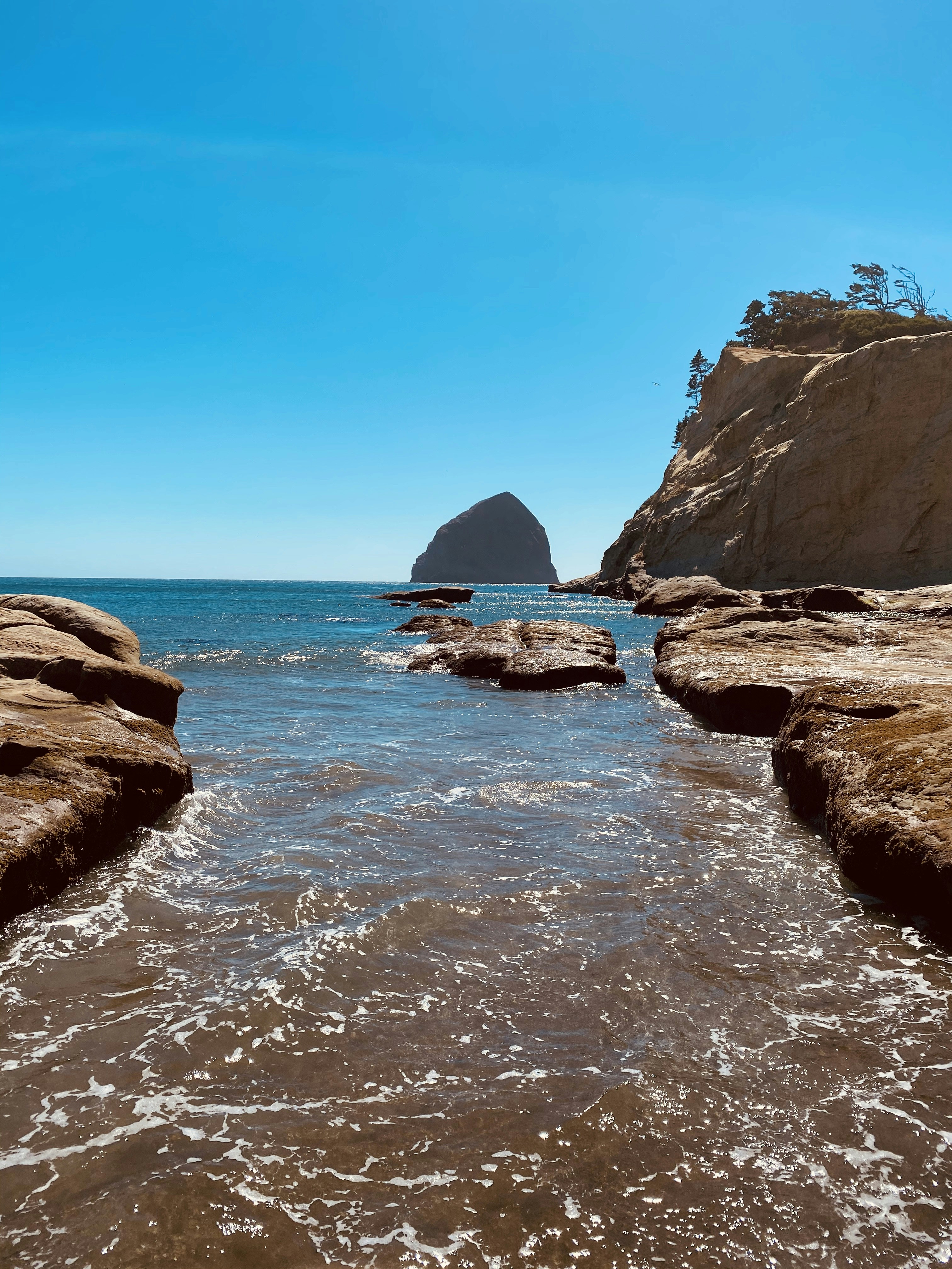 Lone Sea Stack Framed by Tidal Light and Coastal Cliffs