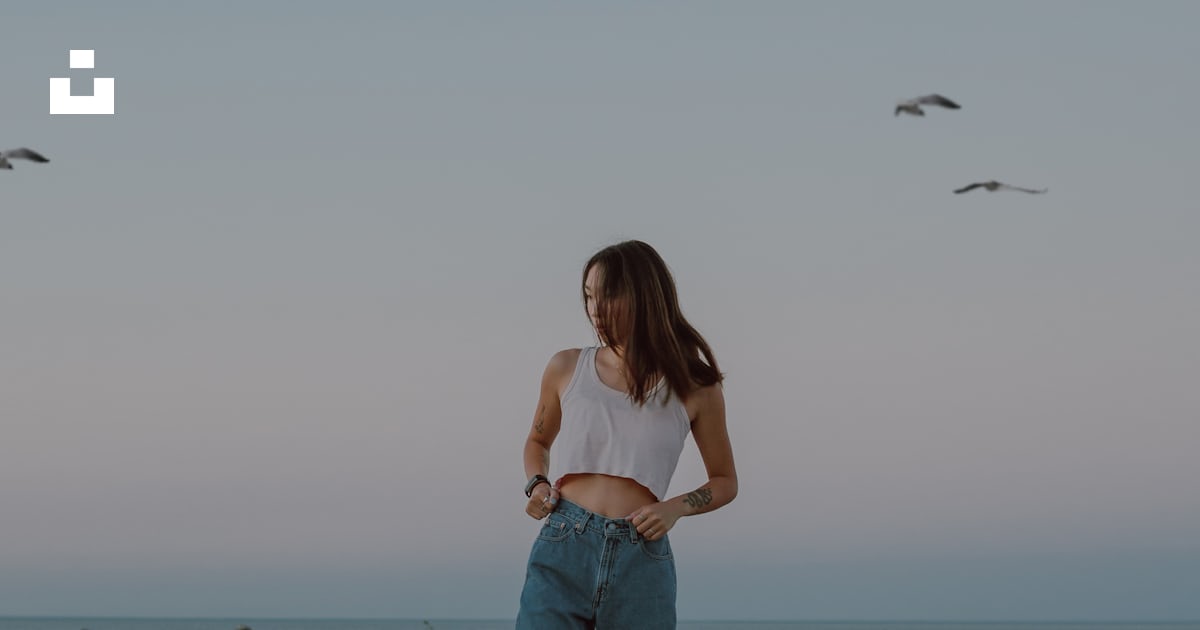 낮 동안 해변에 서 있는 파란색 데님 청바지를 입은 여자 사진 Unsplash의 무료 회색 이미지