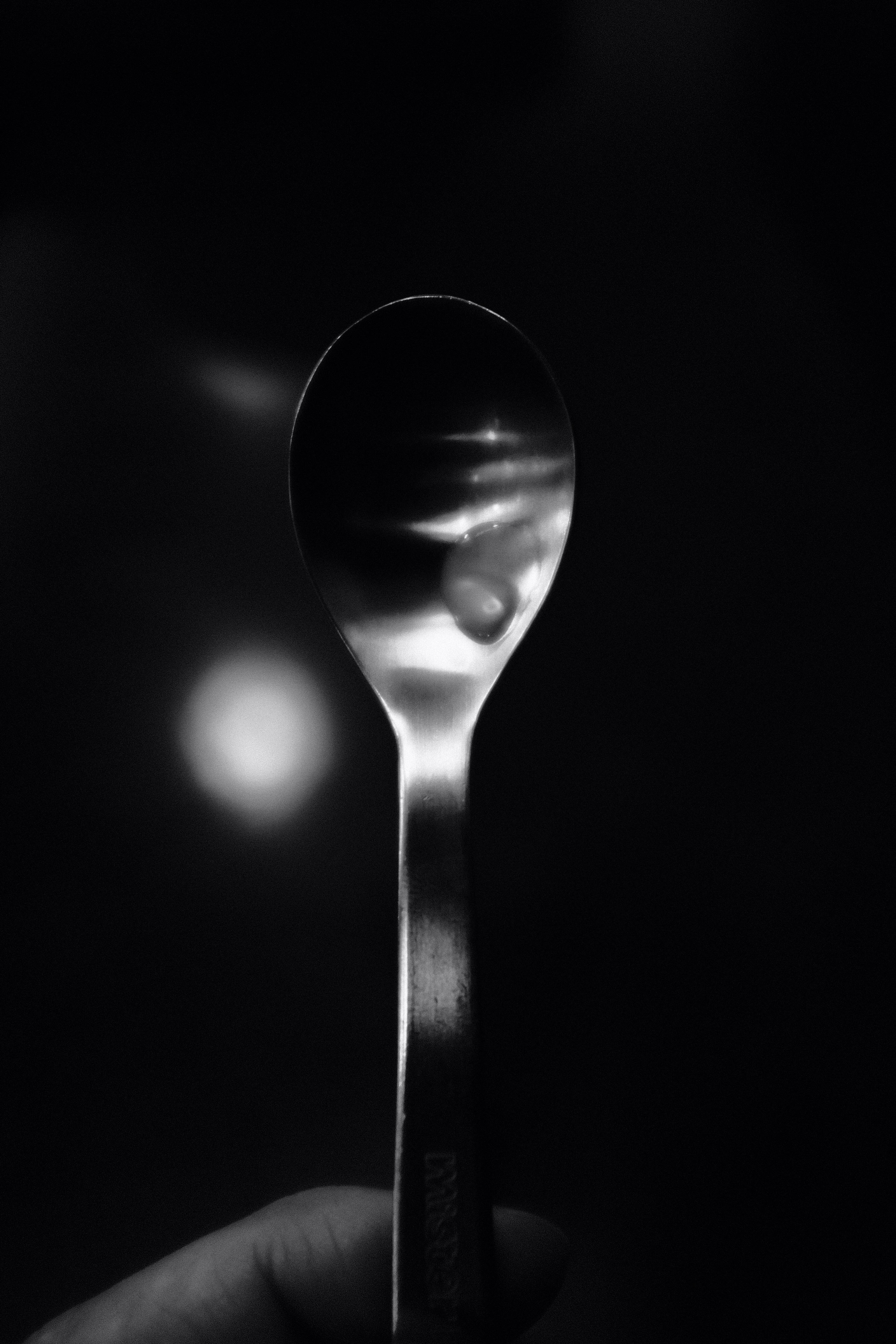 Metal spoon reflecting light patterns against a dark backdrop, showcasing intricate details and textures.
