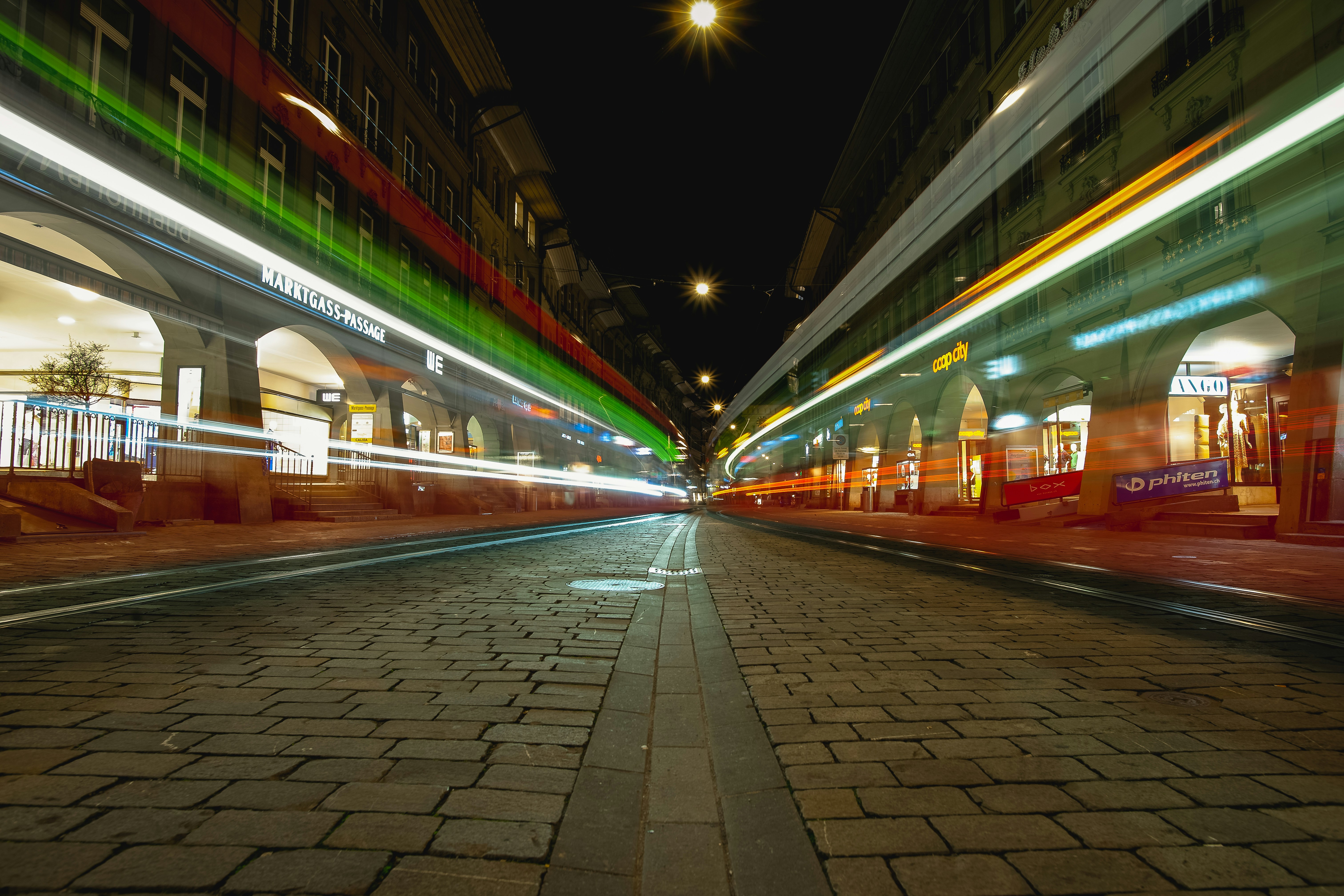 Long exposure of a city street at night with vibrant light trails from passing vehicles.