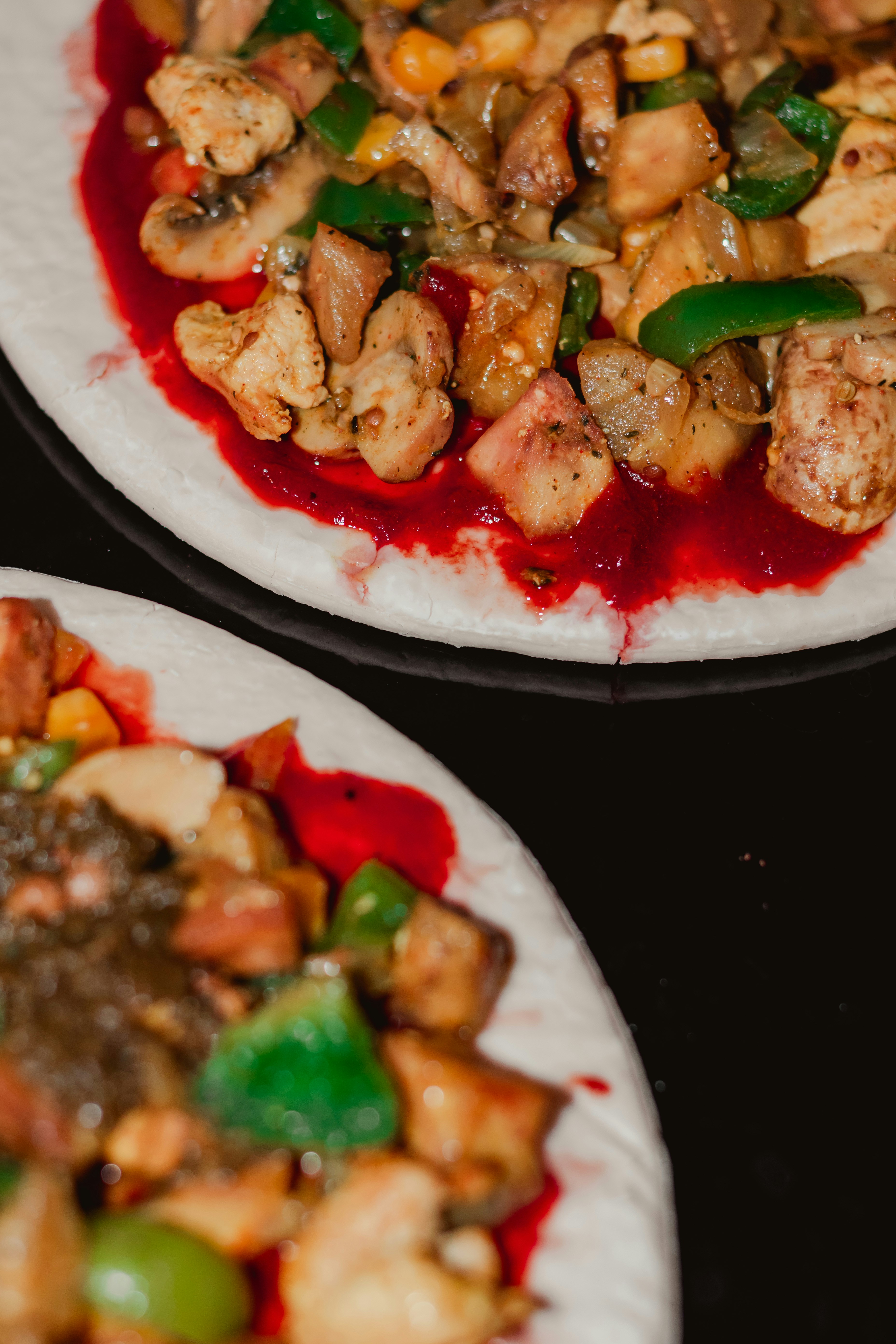 Crimson rims and loaded toppings: two pizzas on a dark canvas