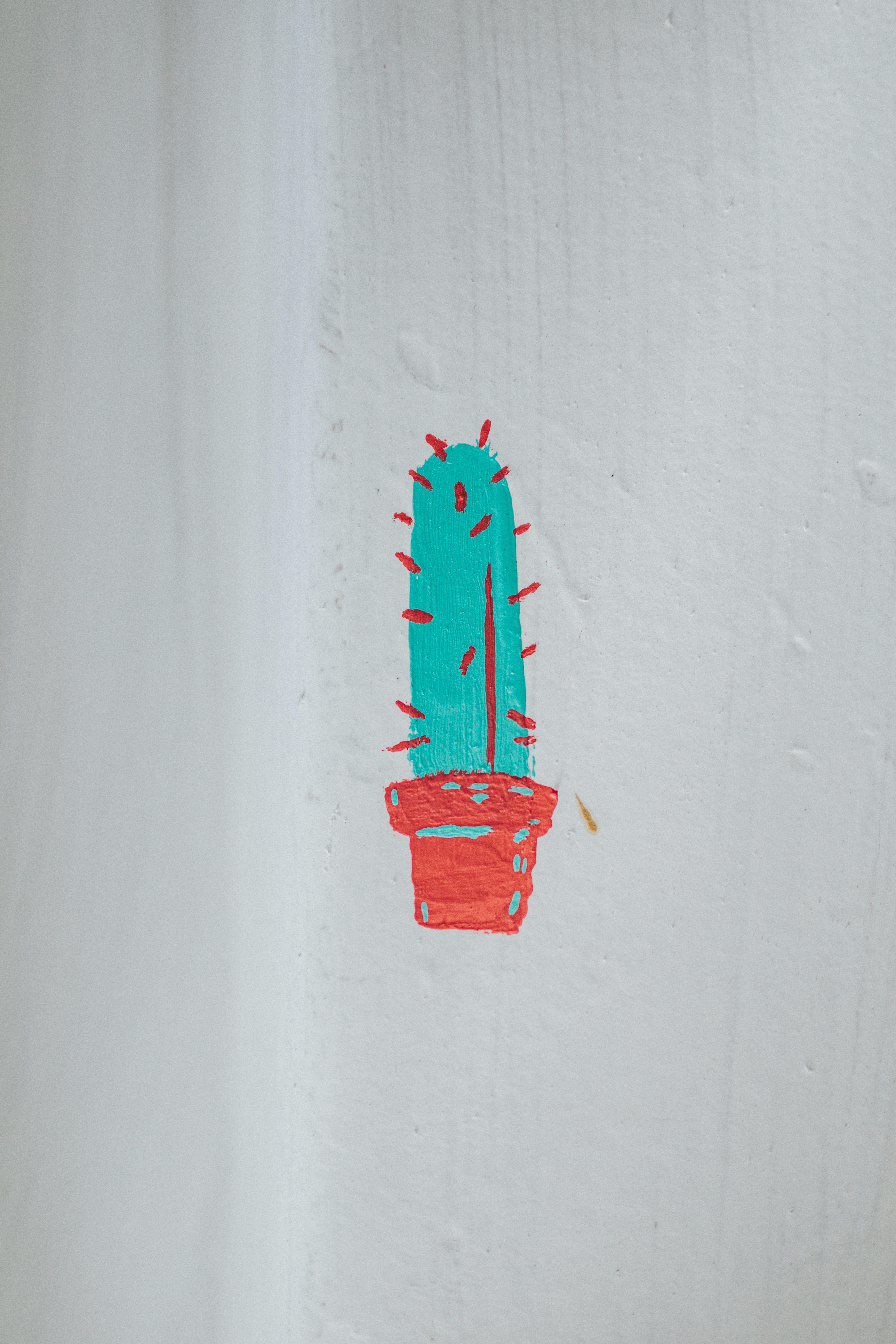 Teal Cactus in a Red Pot Pops Against a Minimal Wall
