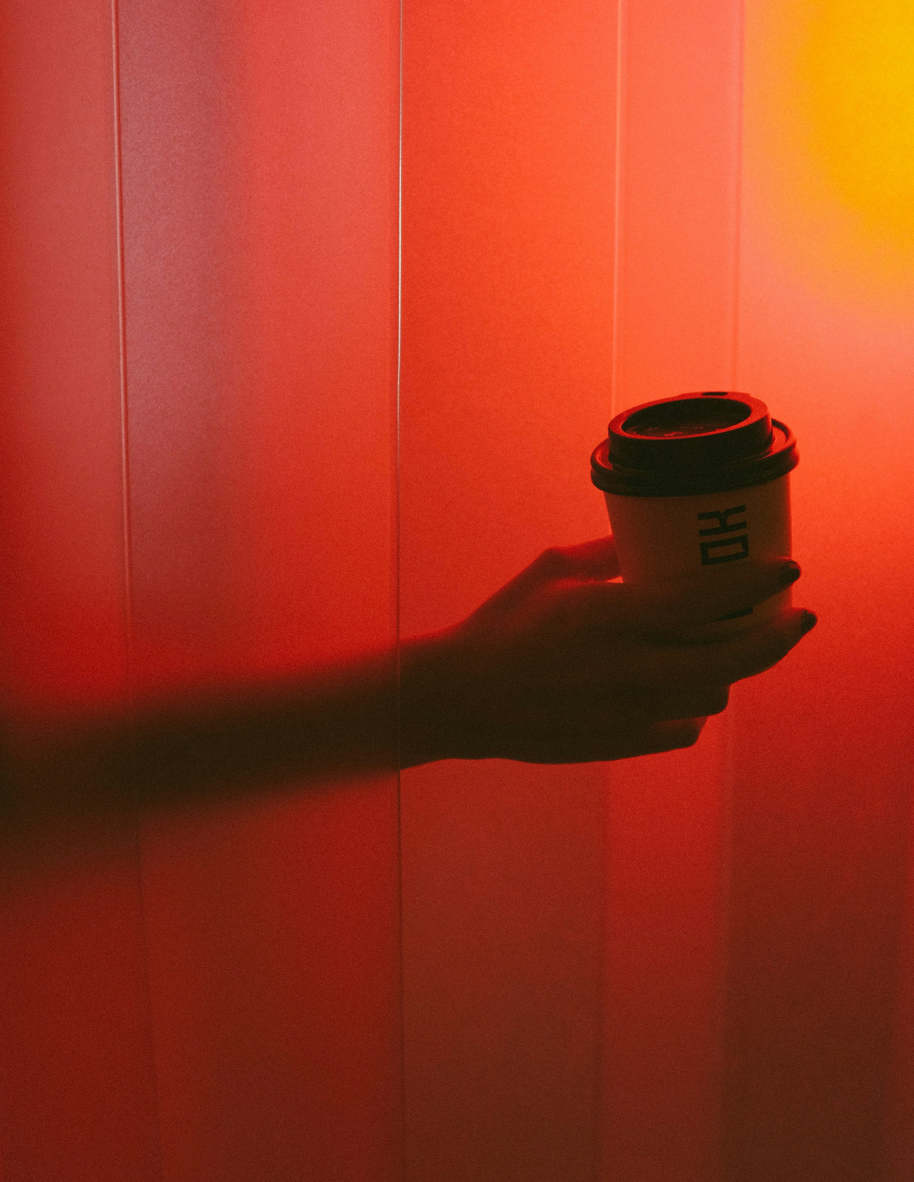 Coffee in Red: A Shadowy Hand with a To-Go Cup