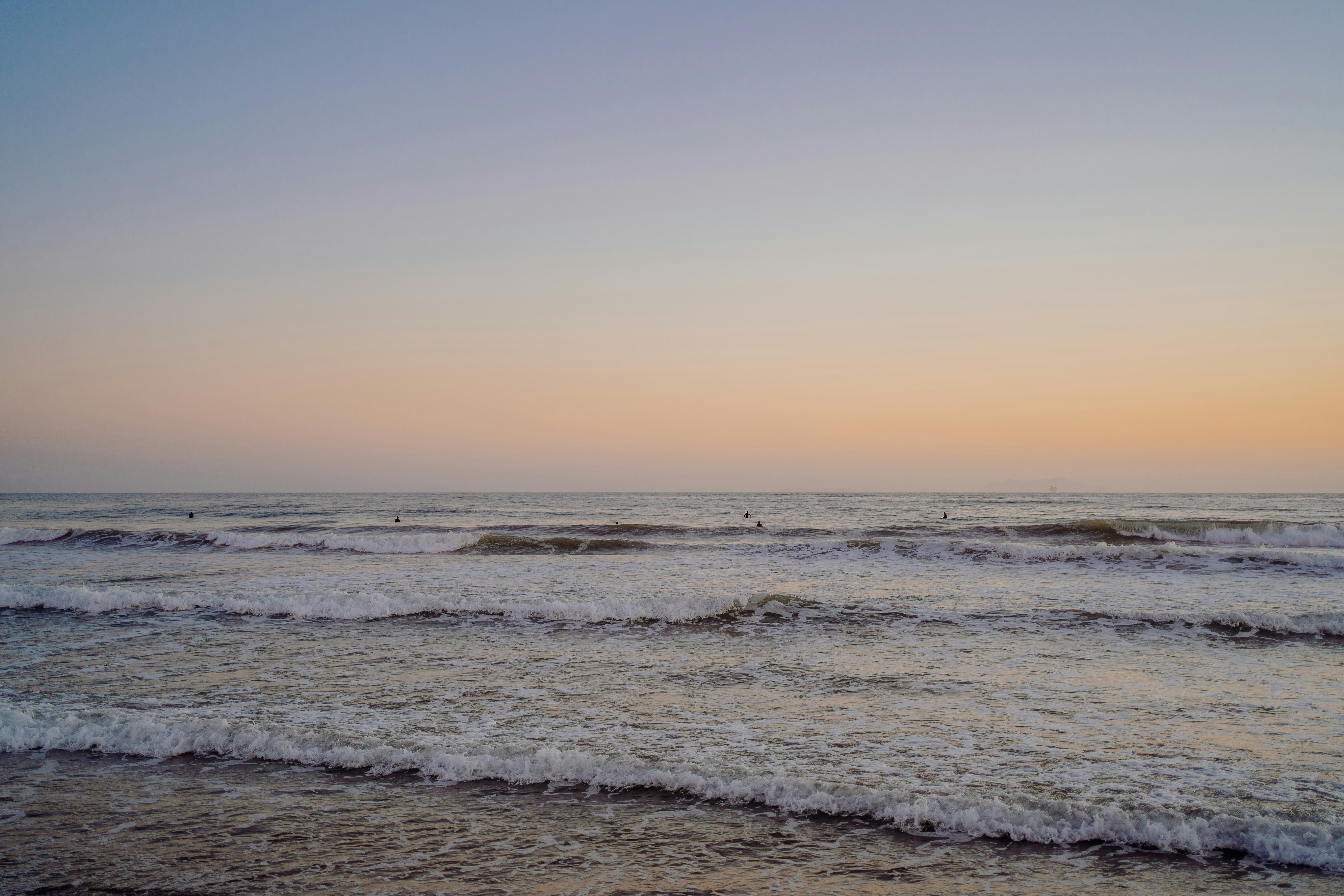Calm ocean waves under a pastel sunset sky.