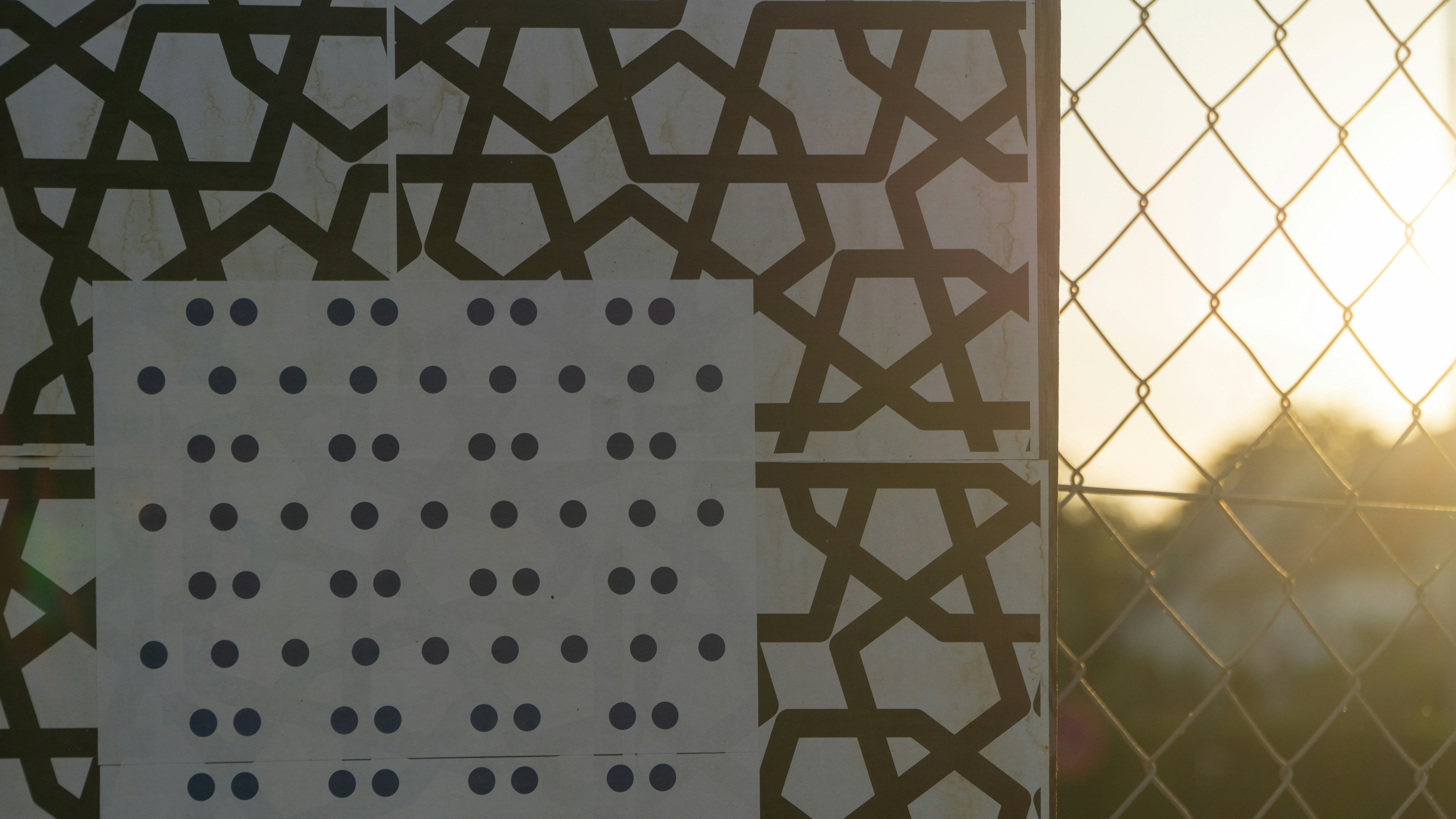 Dotted Panel at Sunset, Framed by Chain-Link Mesh