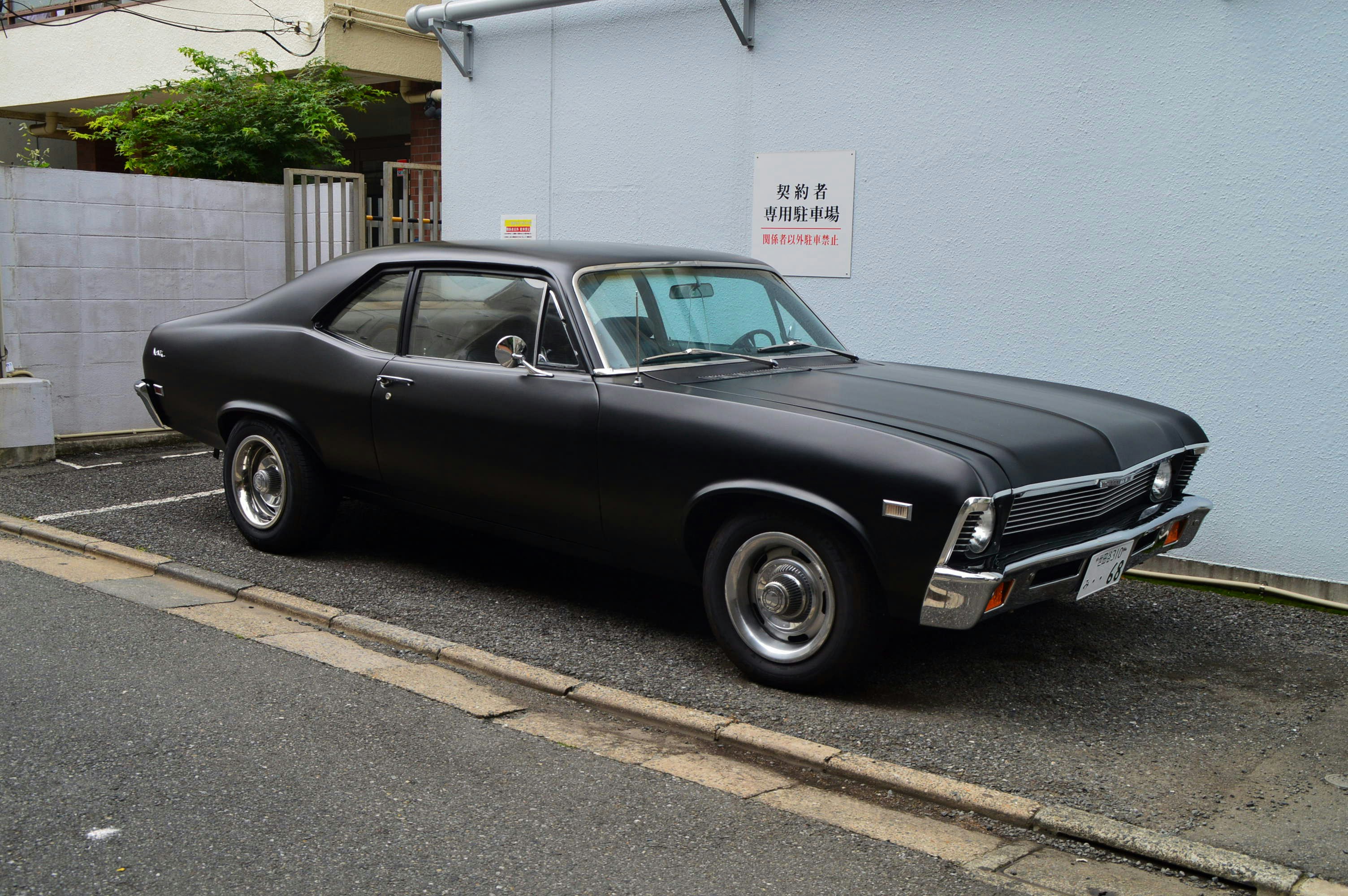 Classic matte black muscle car parked on a quiet street, showcasing its sleek lines and vintage design.