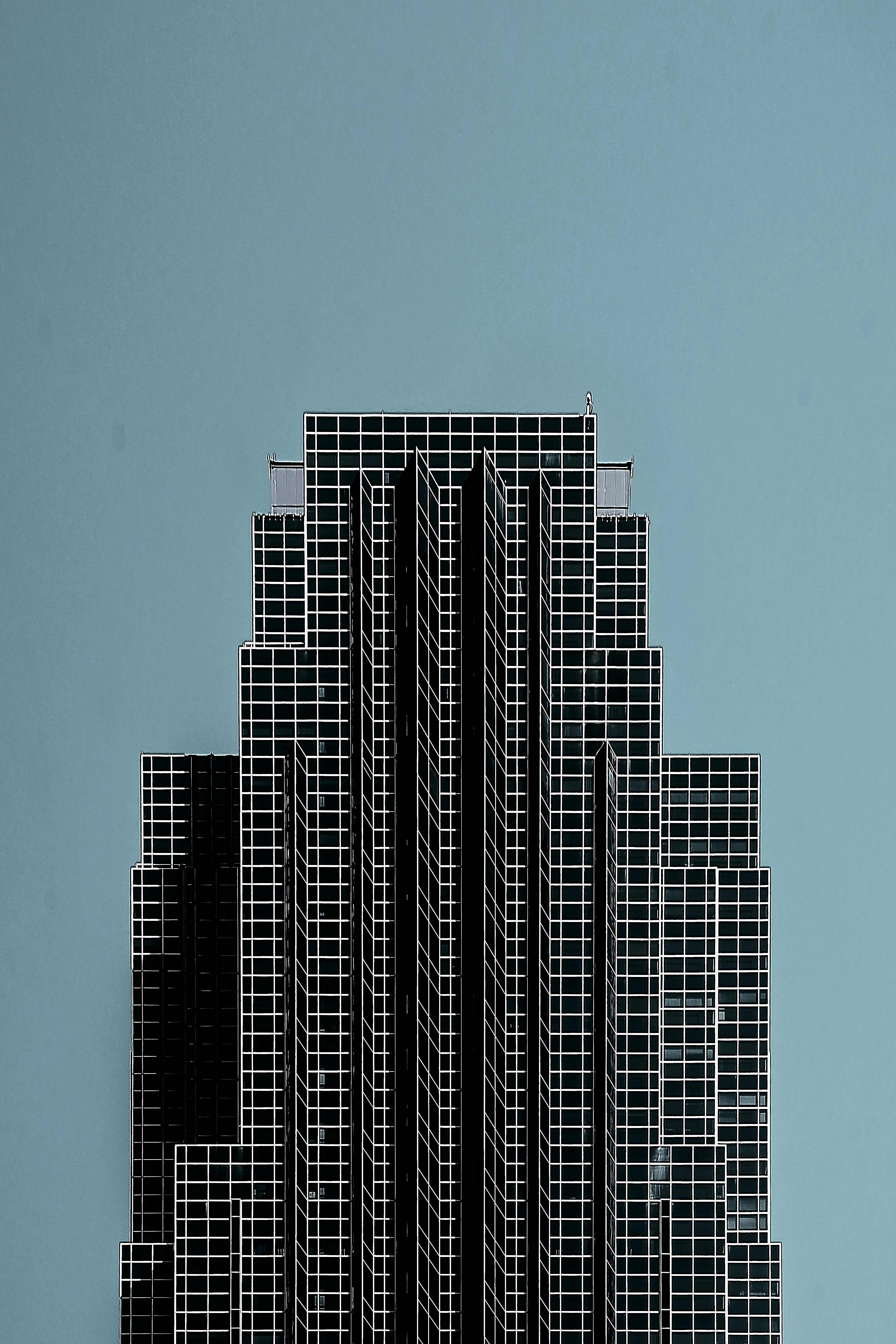 Gridded Summit: A Tiered Tower Rising Against a Serene Blue Sky