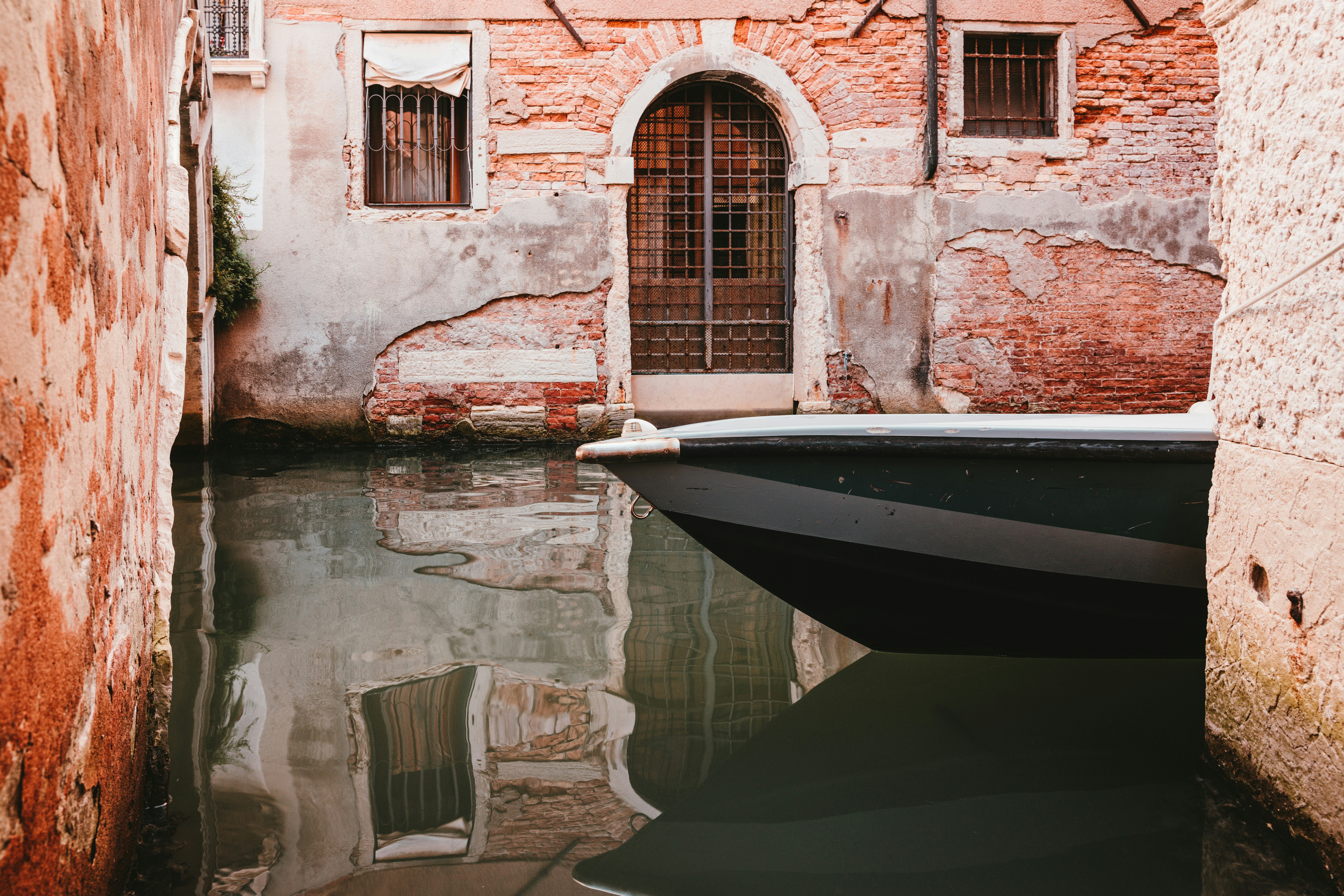 Archway Over the Canal: Brick Walls, Boat Bow, and Reflective Water