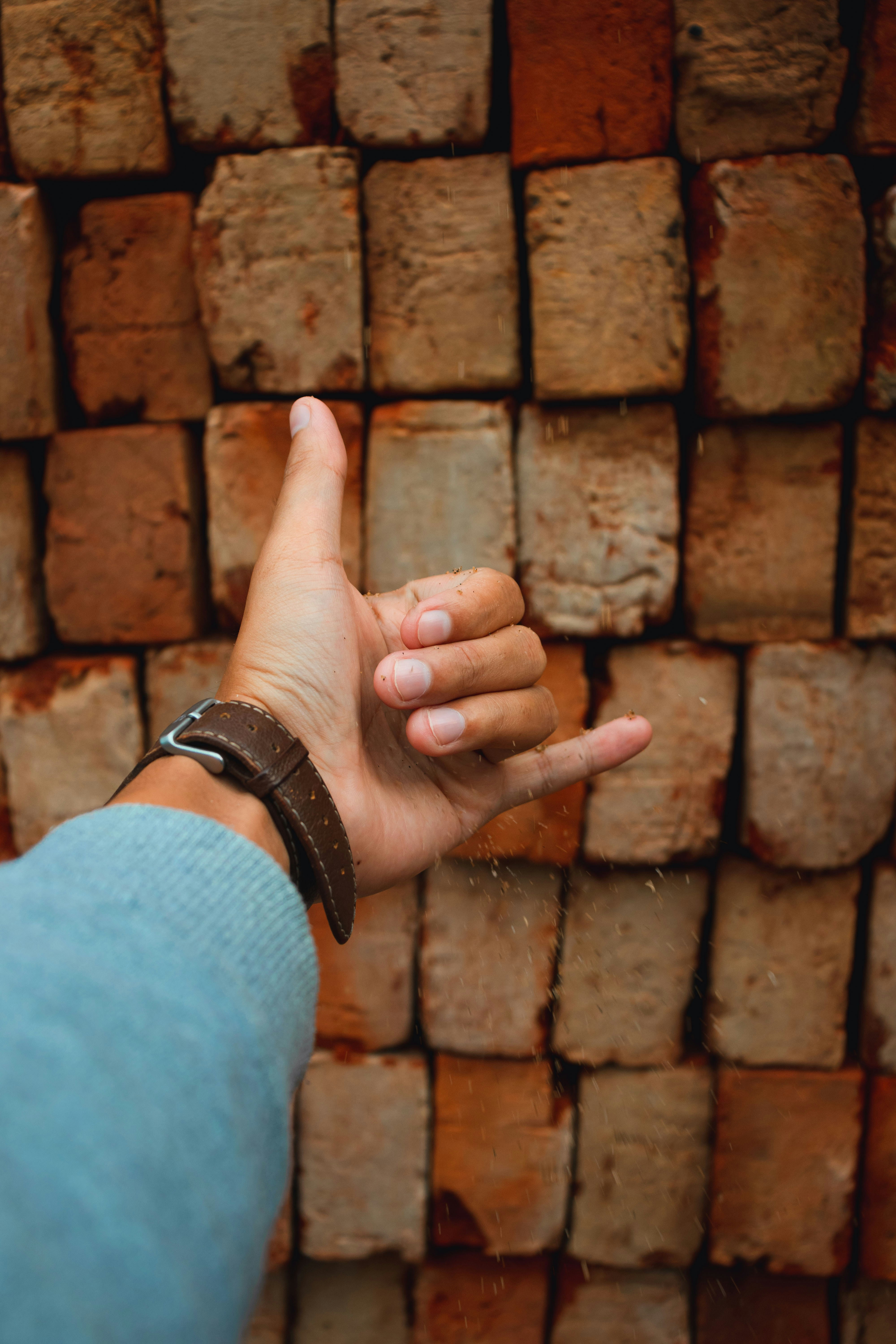 Thumbs Up to Stacked Bricks: A Close-Up Hand Gesture in Soft Focus