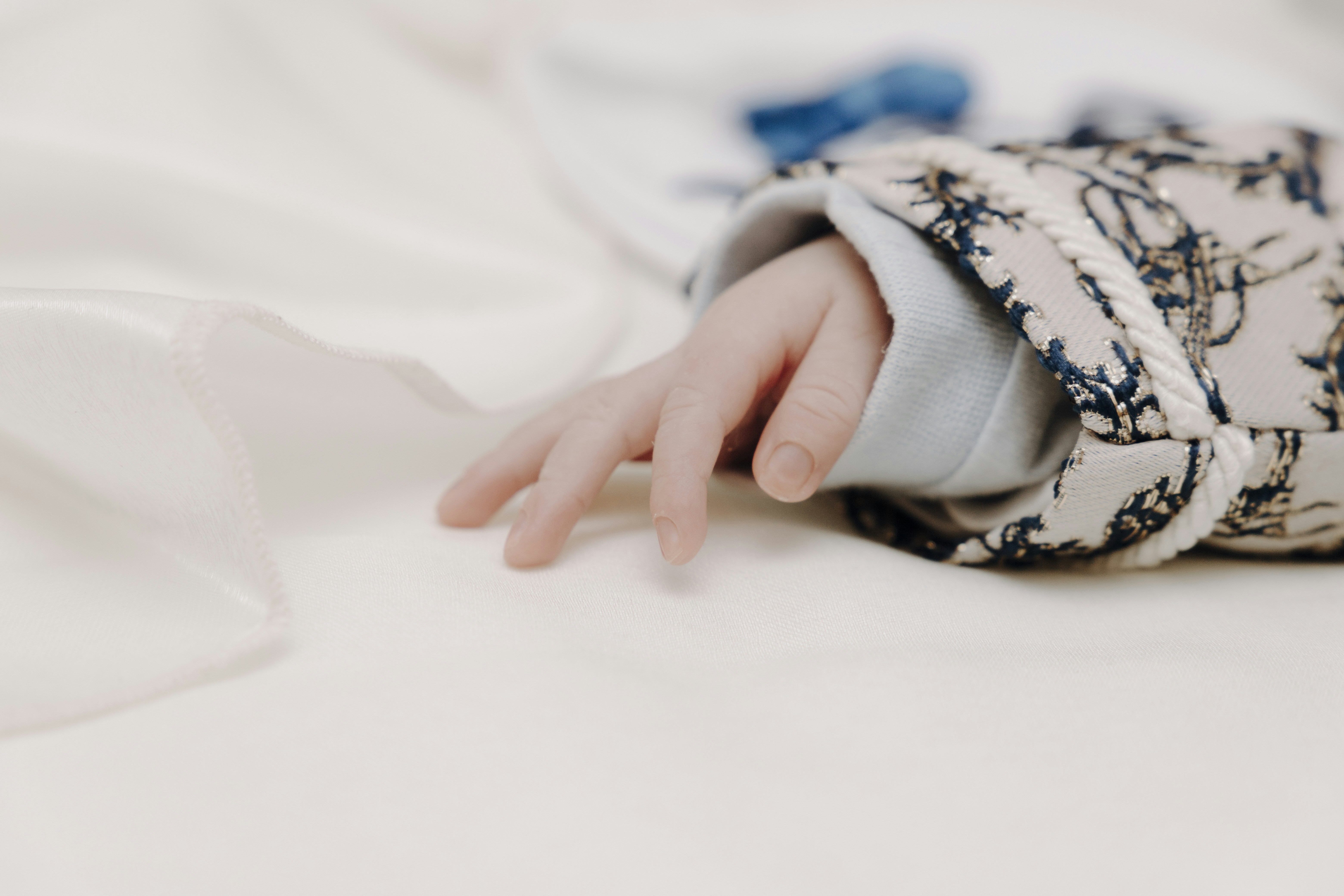 Gentle Clasp: A Baby’s Hand Resting on Soft Linen