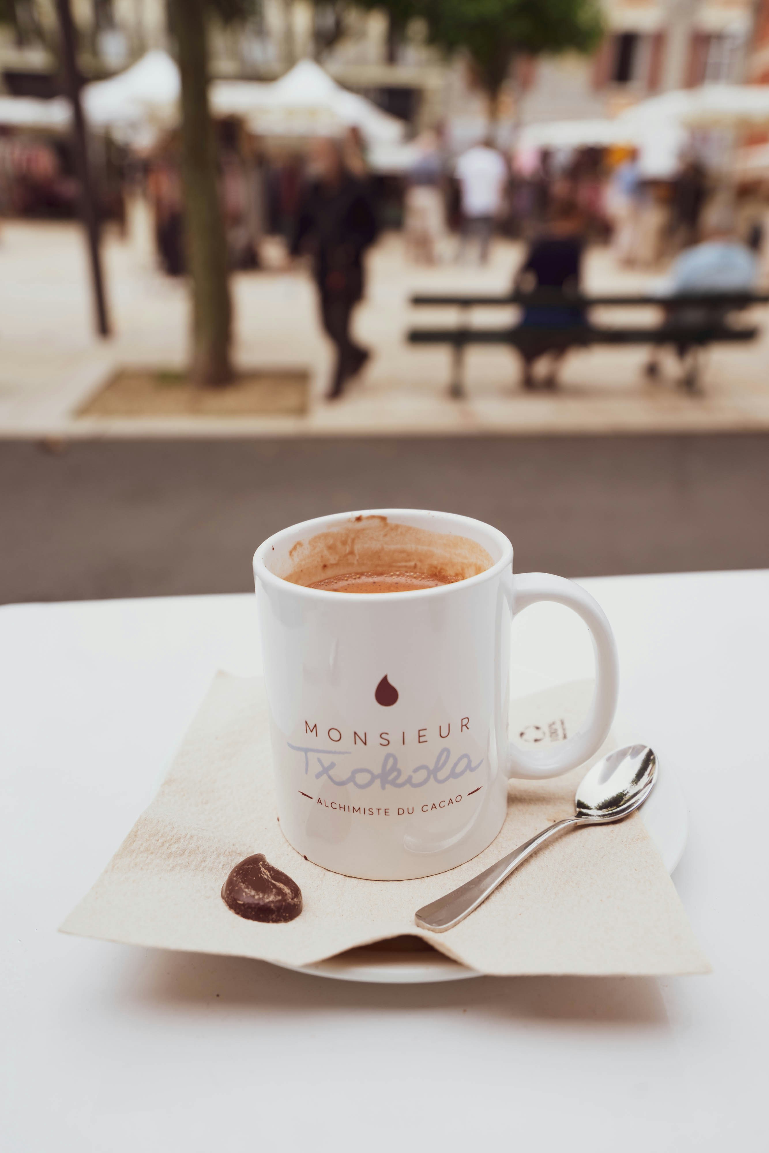 Latte in Focus, City in Blur: A Quiet Café Moment on a Busy Plaza