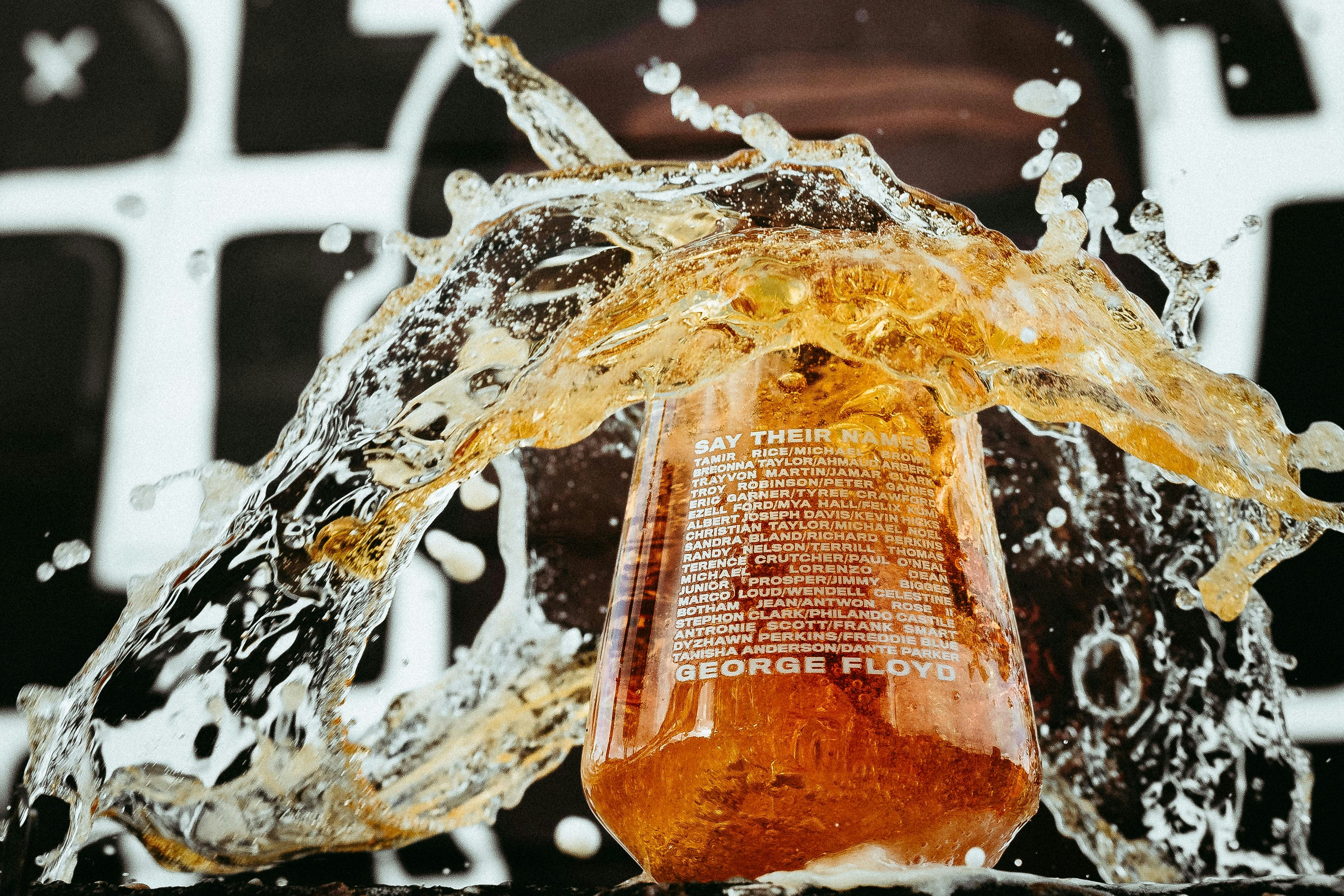 Amber Crown: A Water-Splashed Bottle Surrounded by Liquid Motion