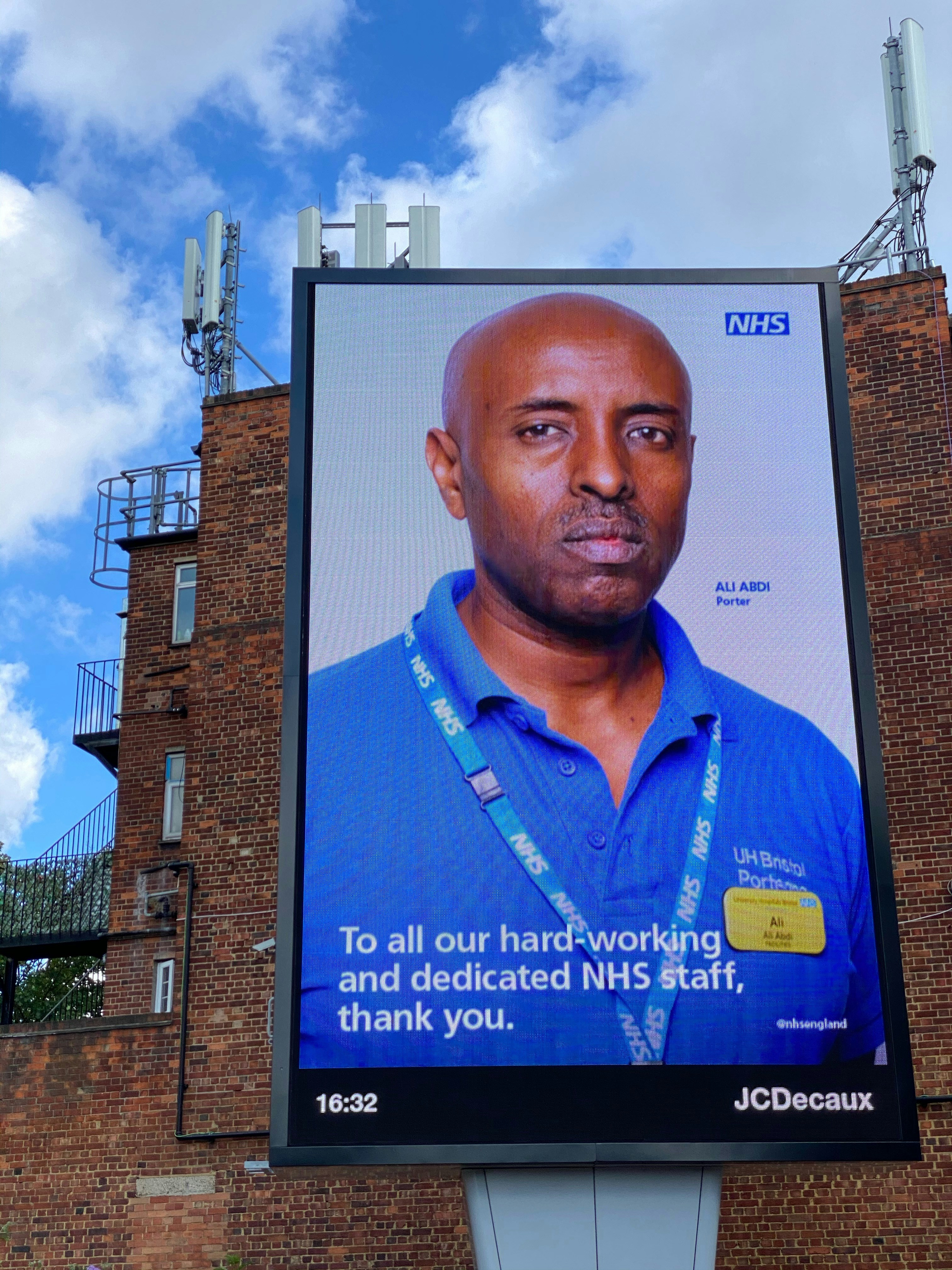 Man in blue polo shirt standing near brown brick building during ...