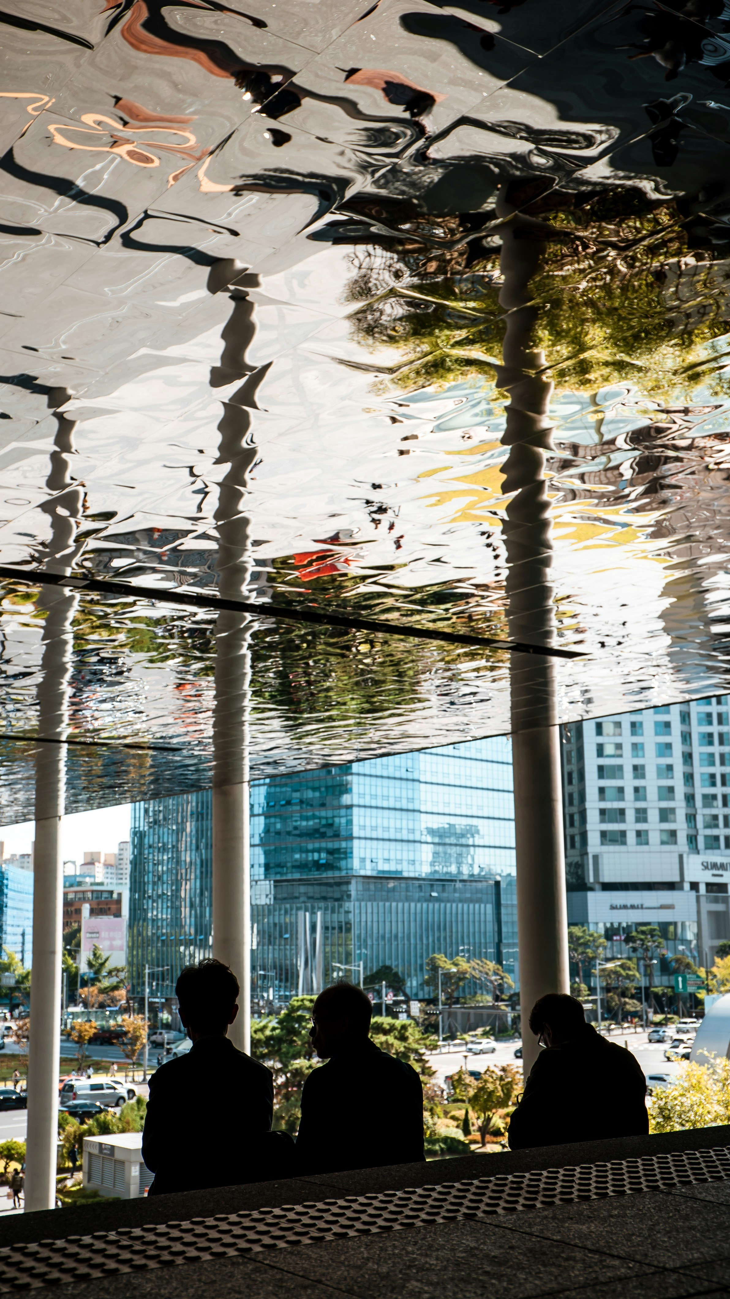 Silhouettes Beneath a Corridor of City Reflections