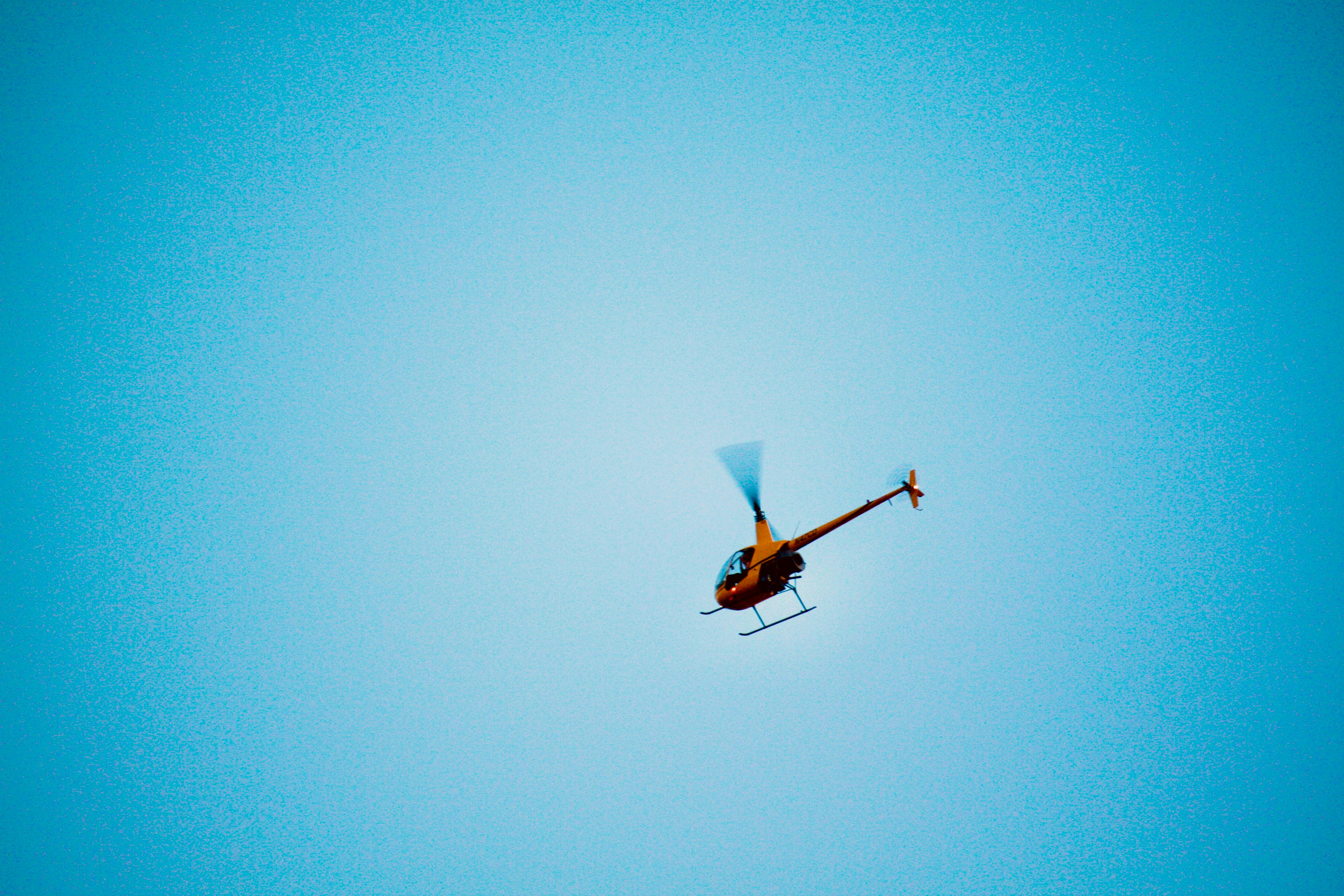 Isolated Orange Helicopter in a Vast Blue Sky