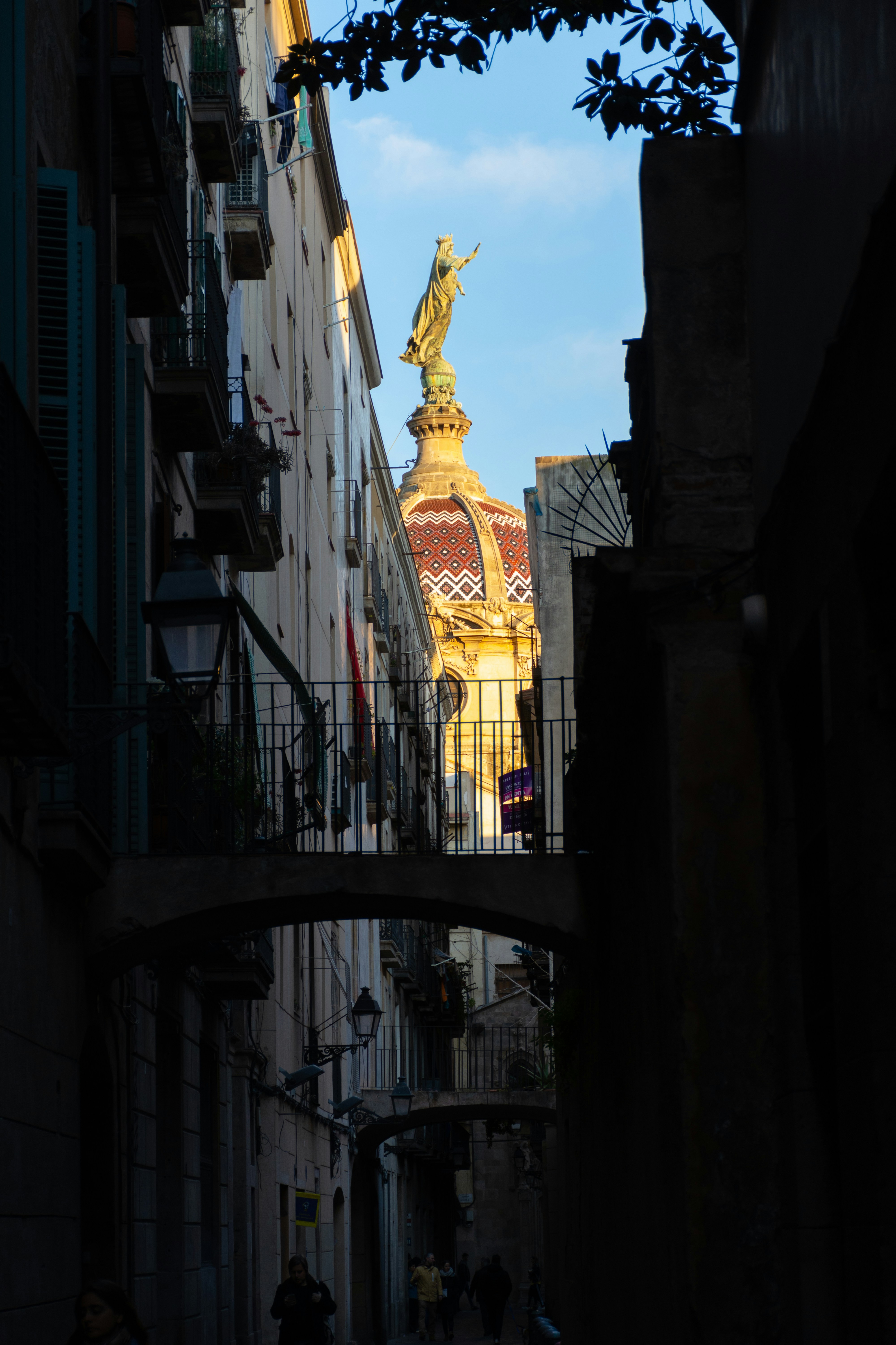 Golden Statue Crowned by Sunlight Above a Narrow Street