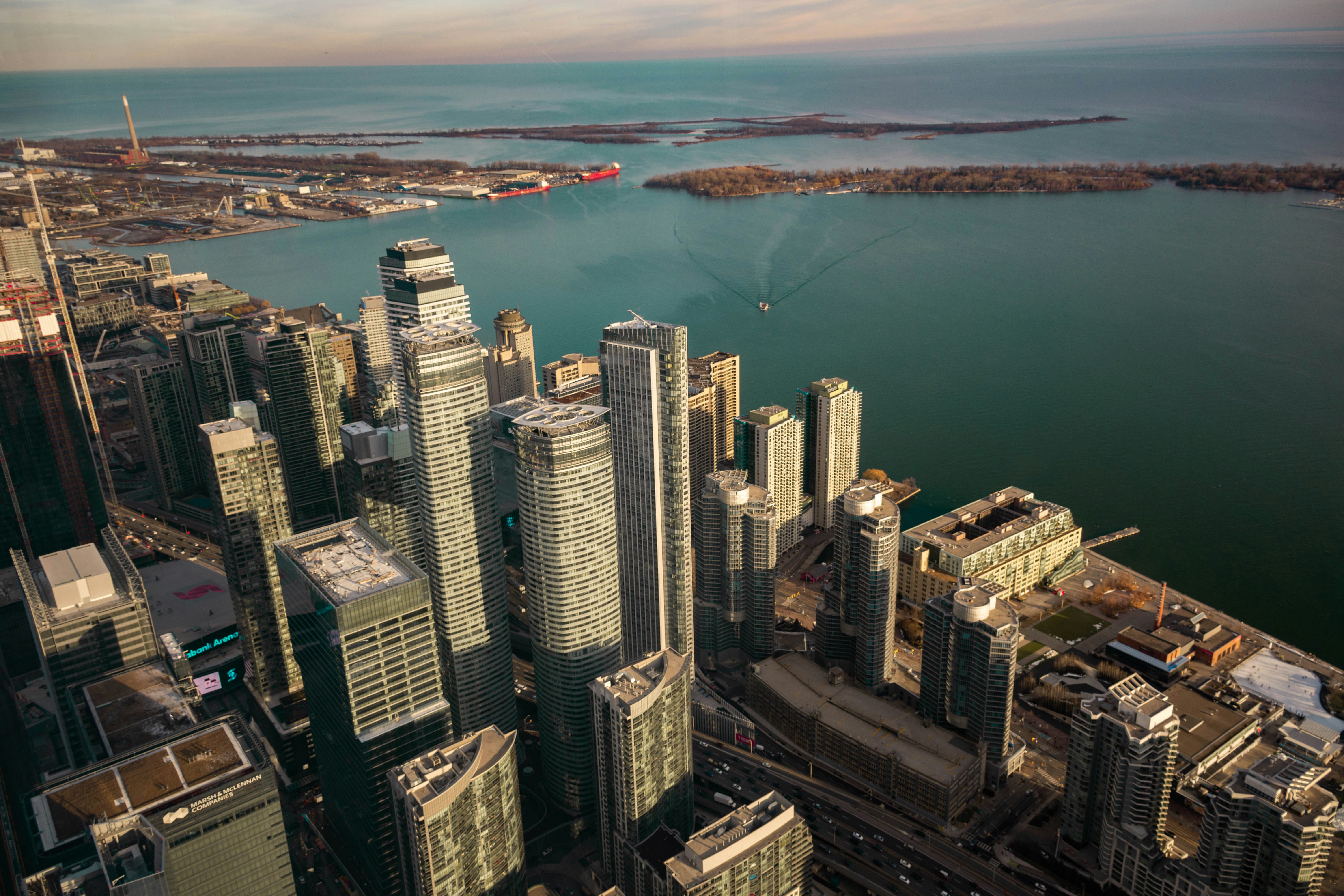 Aerial view of a bustling cityscape with modern skyscrapers alongside a serene body of water, showcasing the contrast between urban life and nature.