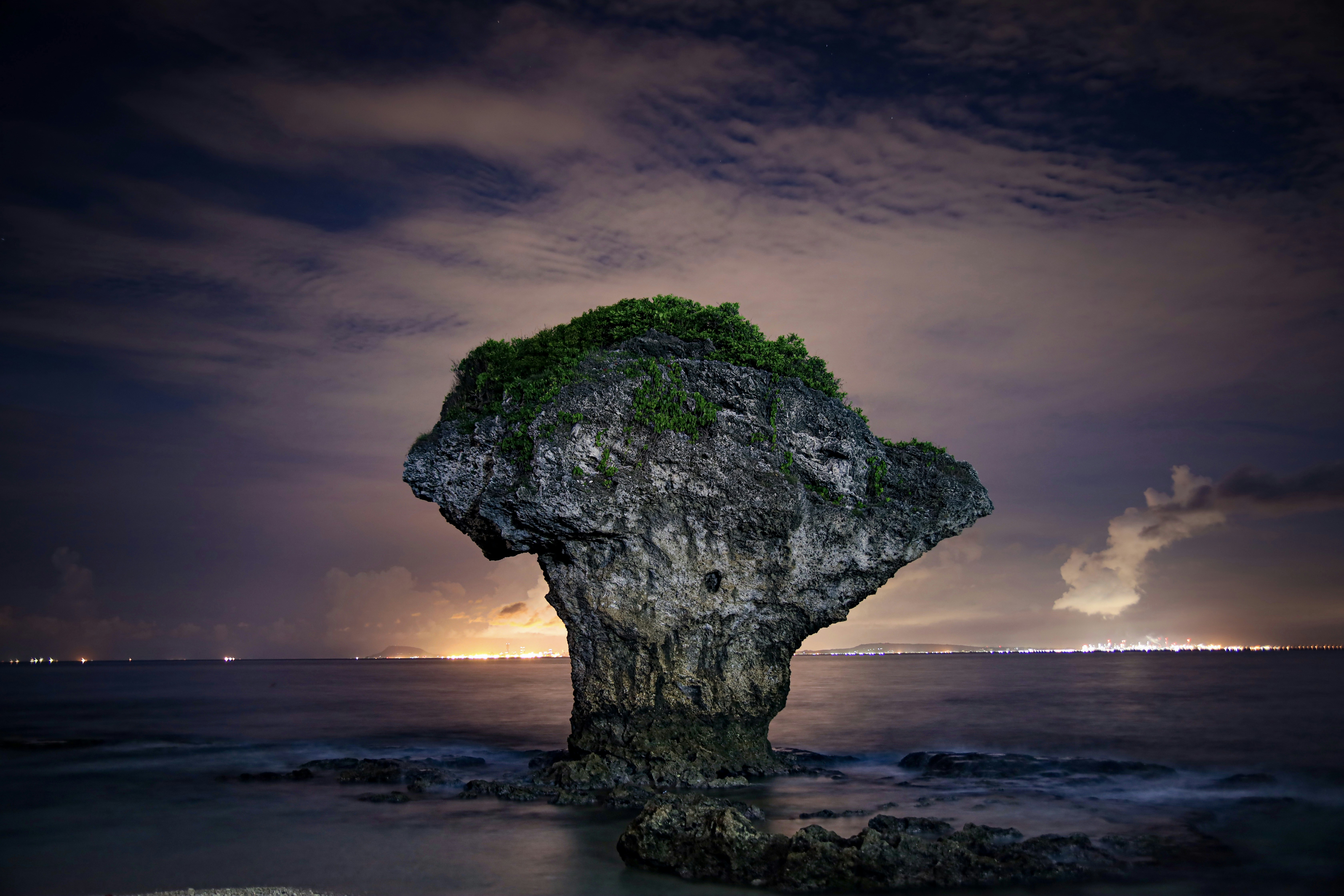 gray rock formation on sea under gray clouds