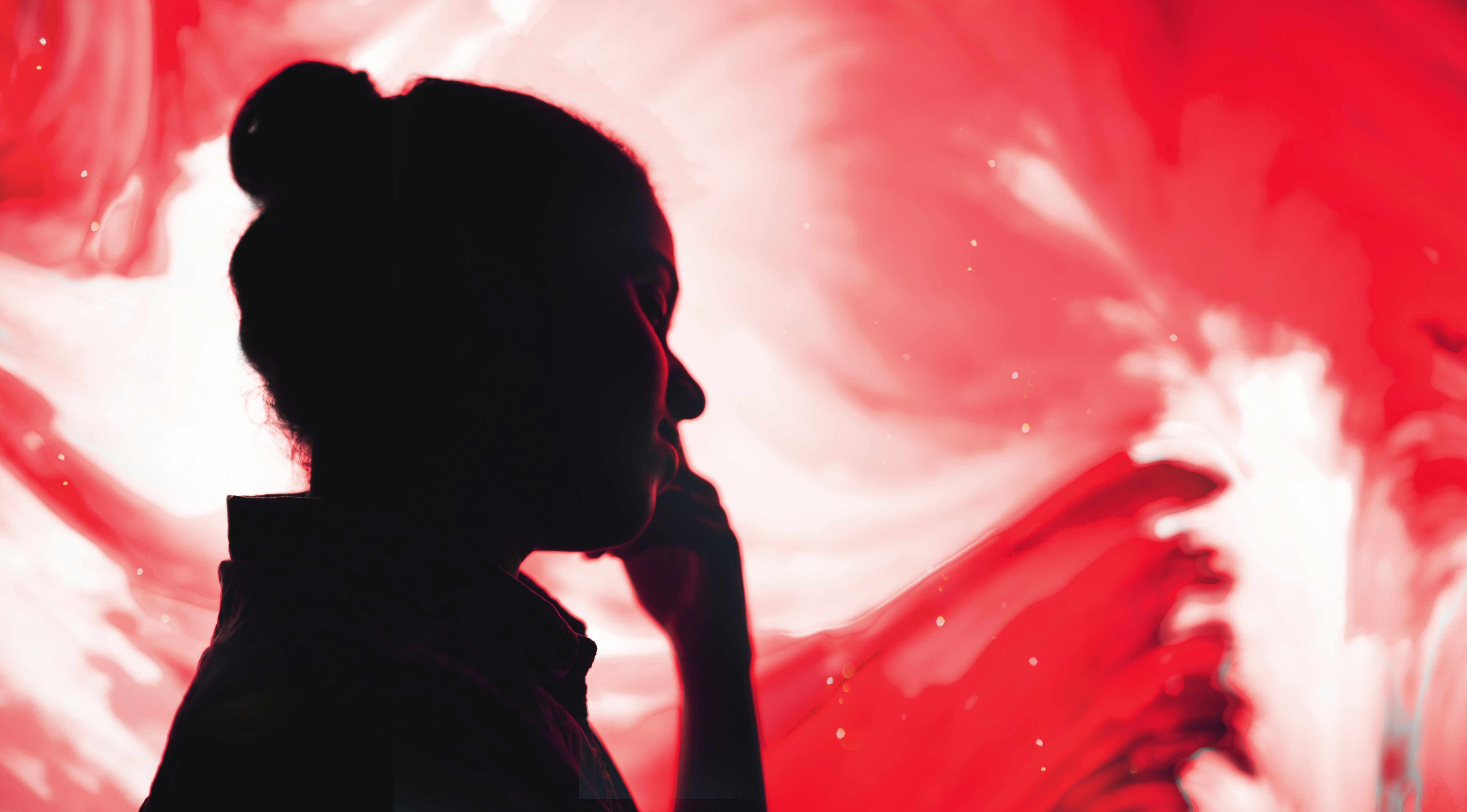 Silhouette of a person engaged in a phone conversation, set against a vibrant red and white abstract background.